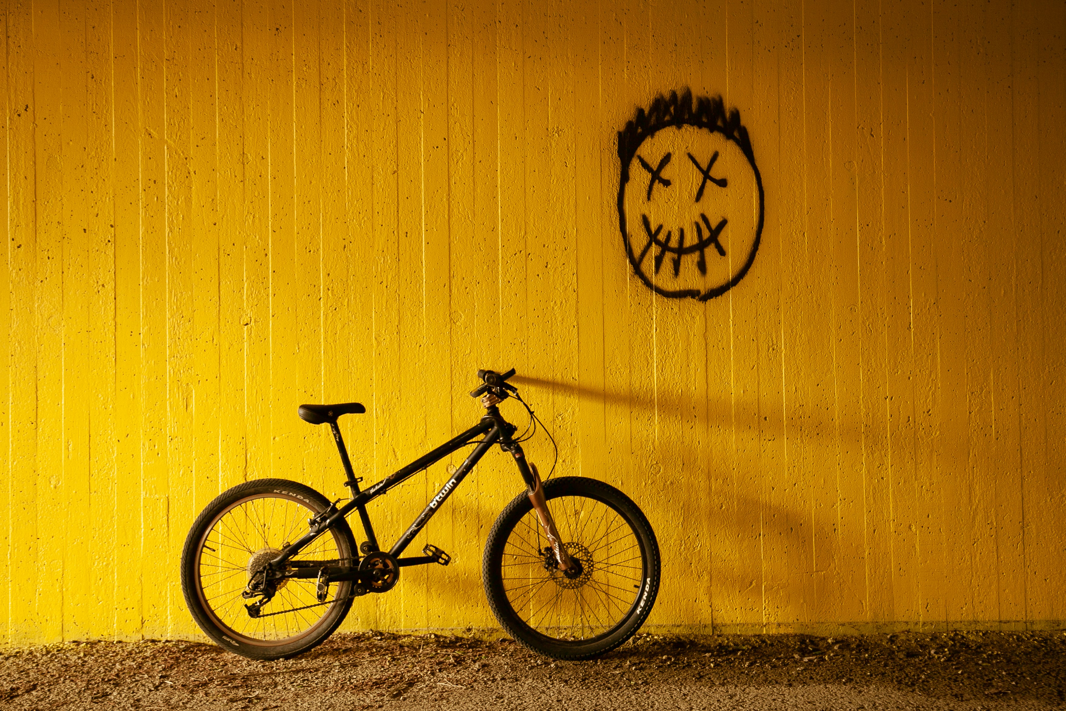 a bicycle parked in front of a wall with a drawing on it