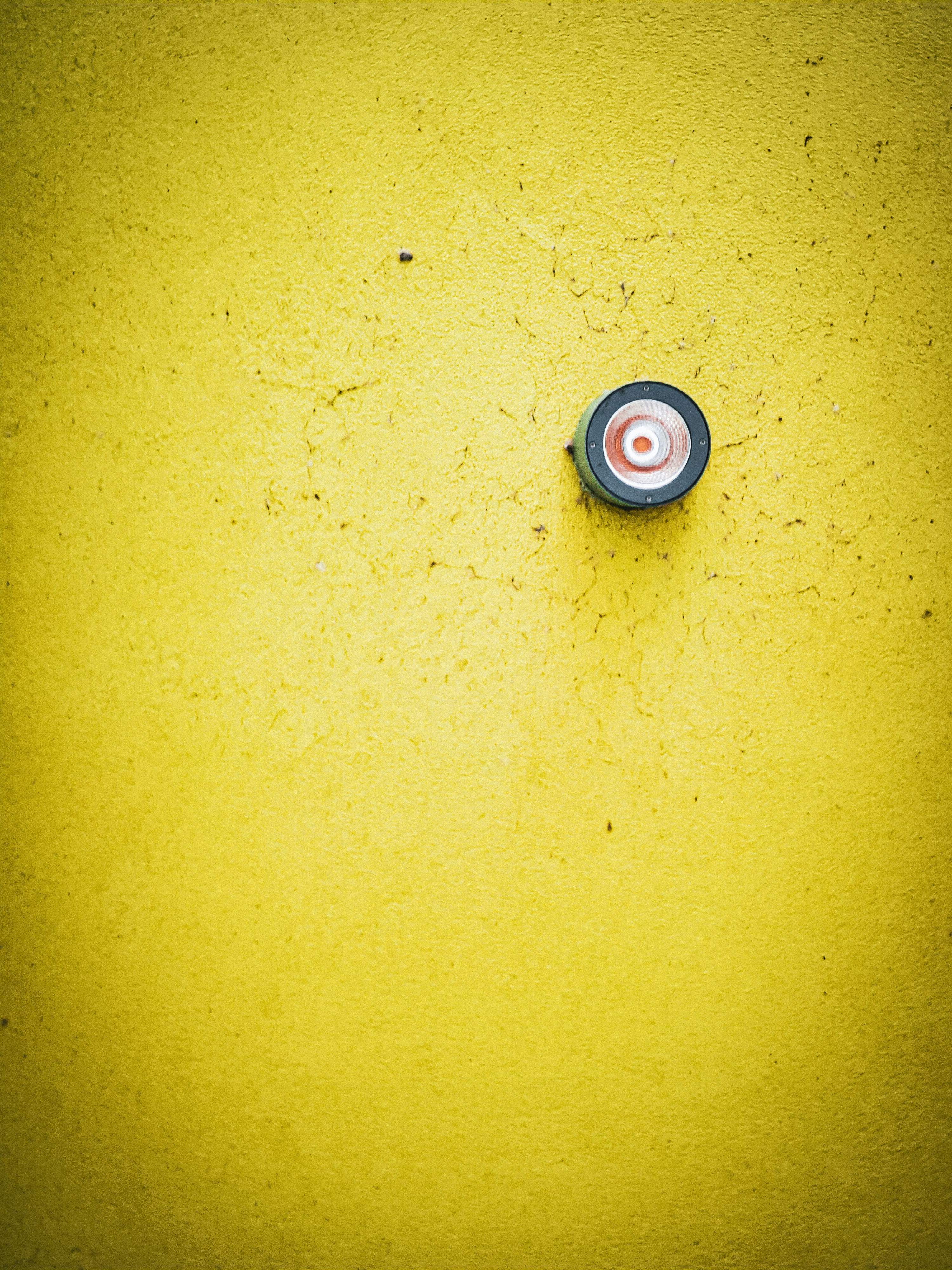 a small black and white button on a yellow wall