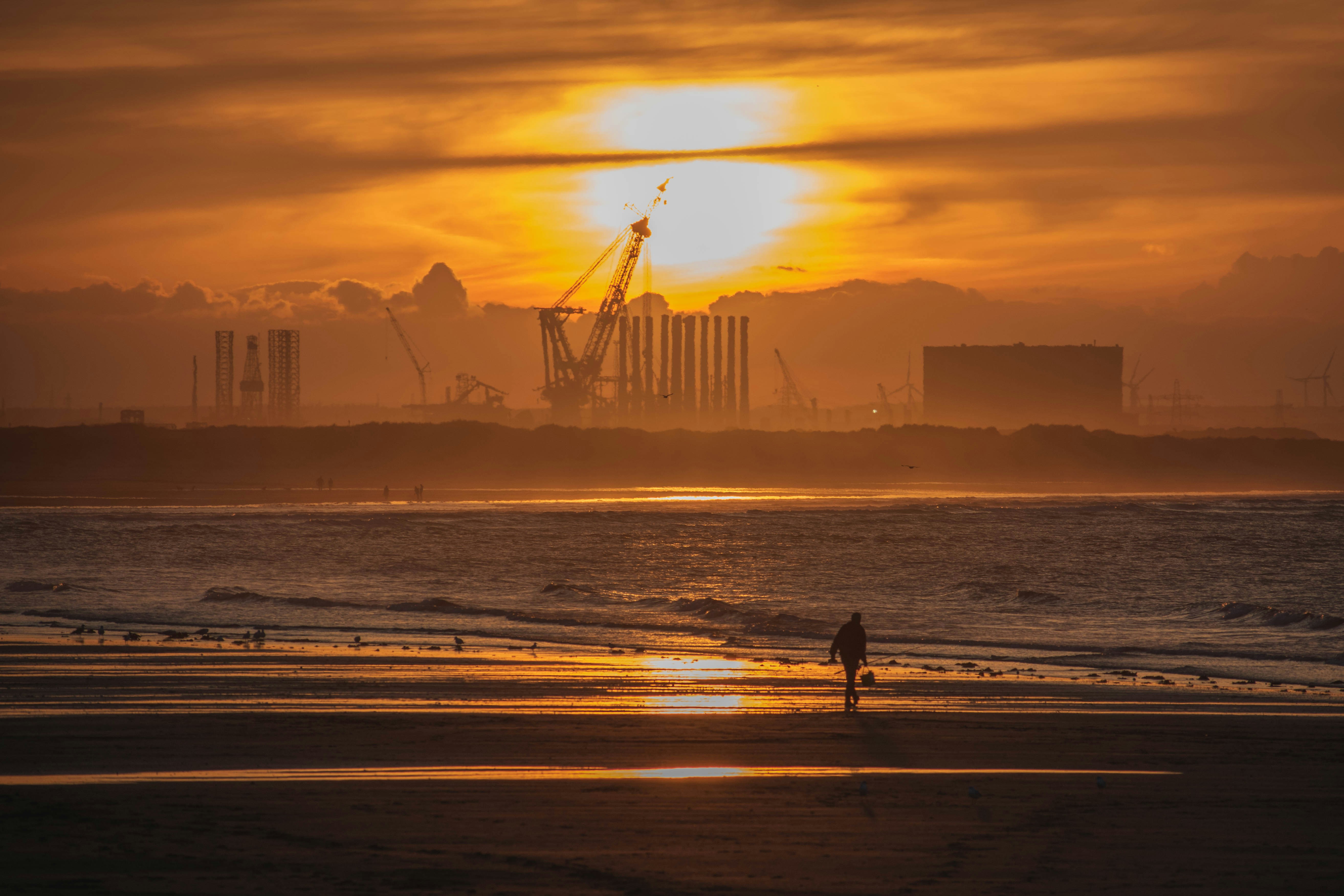 Silhouette at Dusk: Harbor Cranes Behind a Dreamy Beach