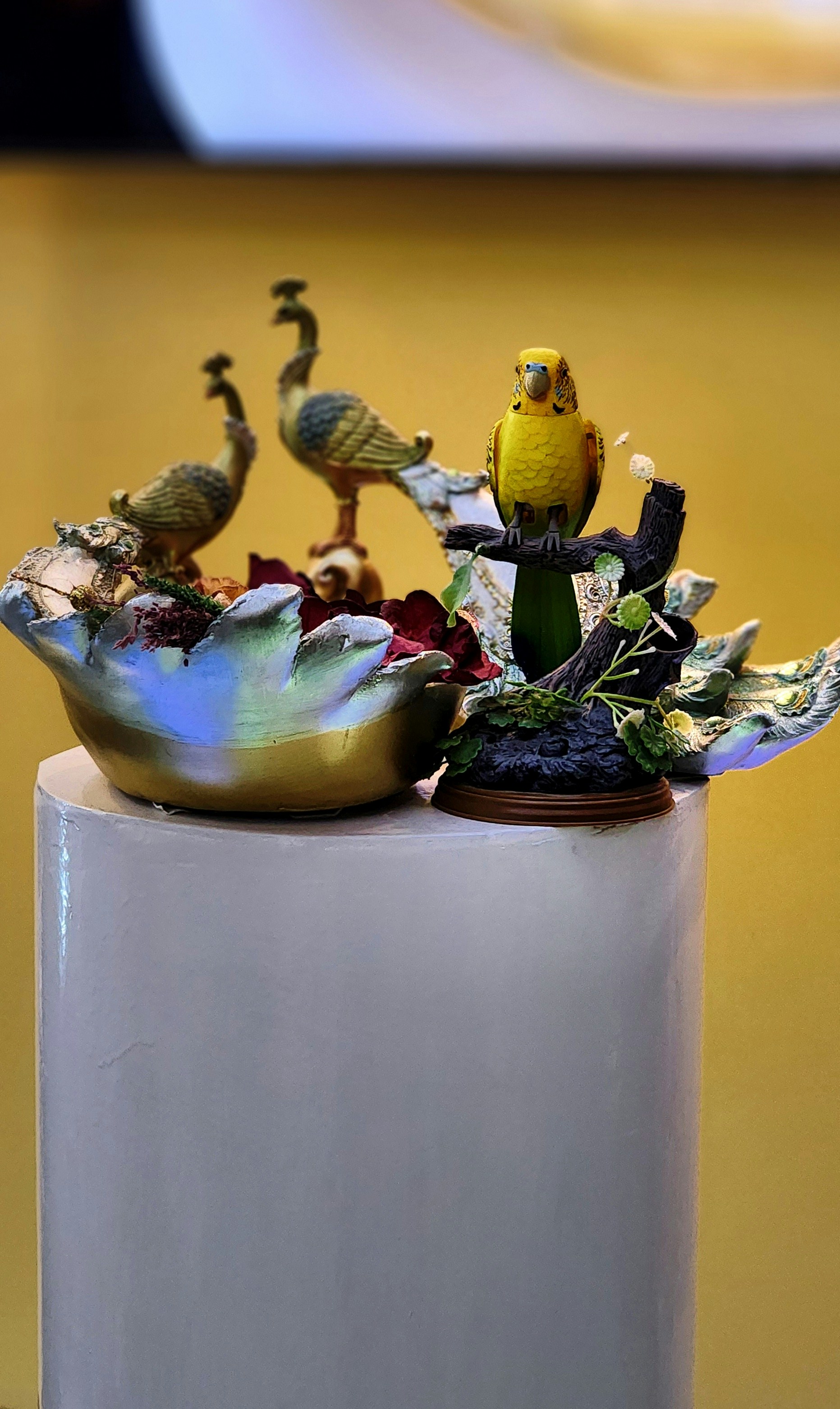 Yellow Parrot on a Ceramic Branch: Quiet Pop of Color on a Painterly Pedestal