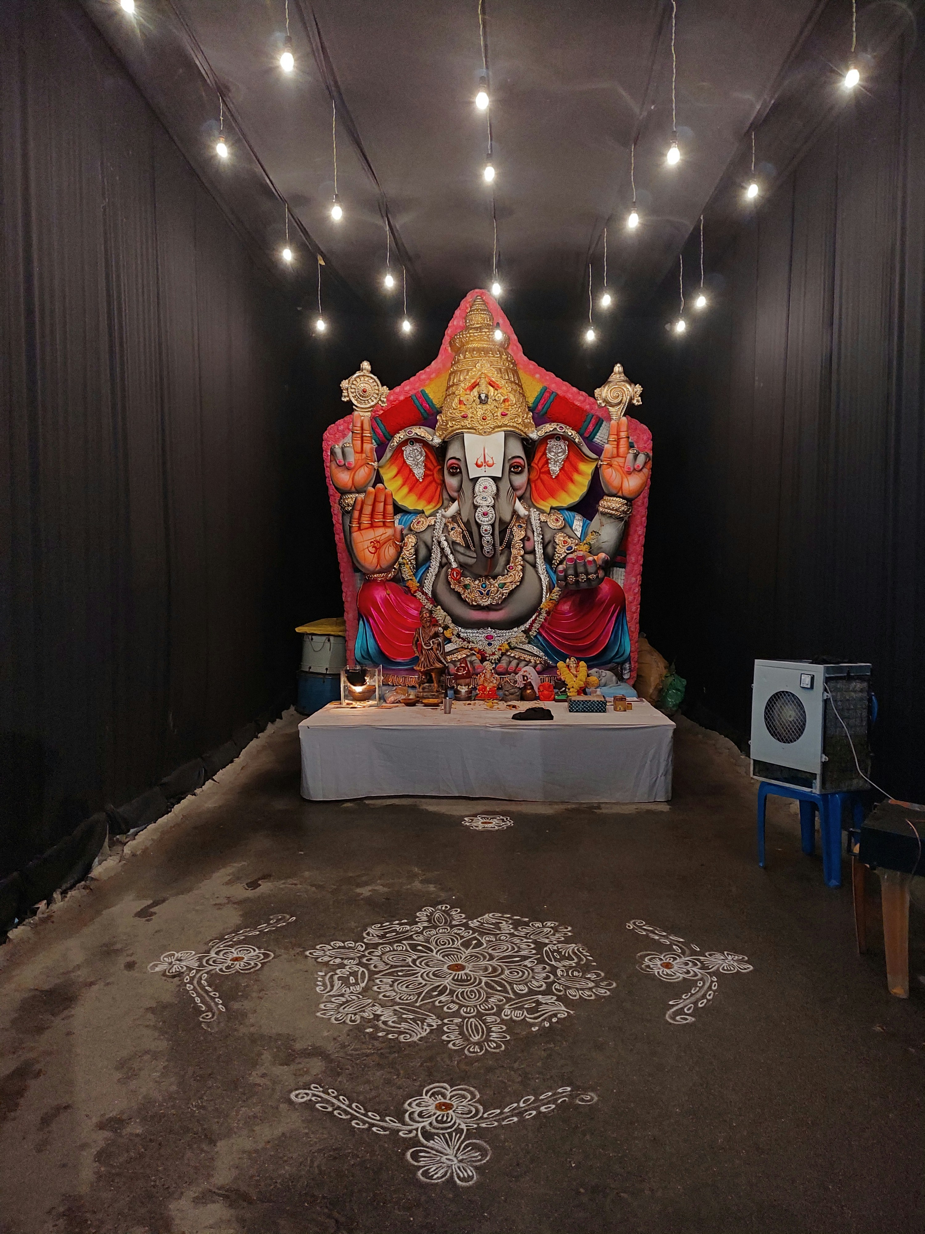 Vivid statue of a deity surrounded by glowing lights in a dimly lit hall.