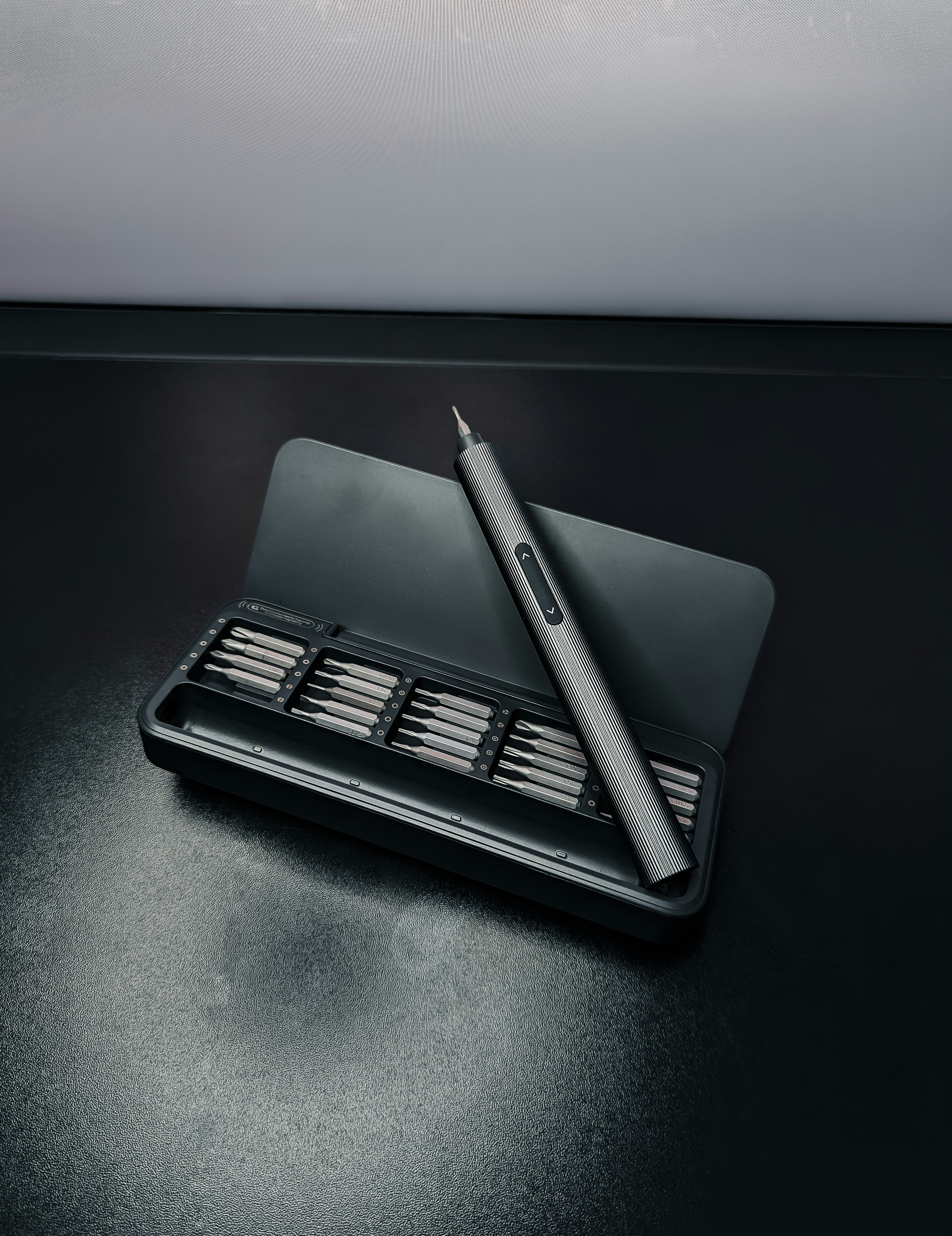 A sleek, modern toolset featuring a precision pen and interchangeable bits, arranged on a dark surface for an elegant display.