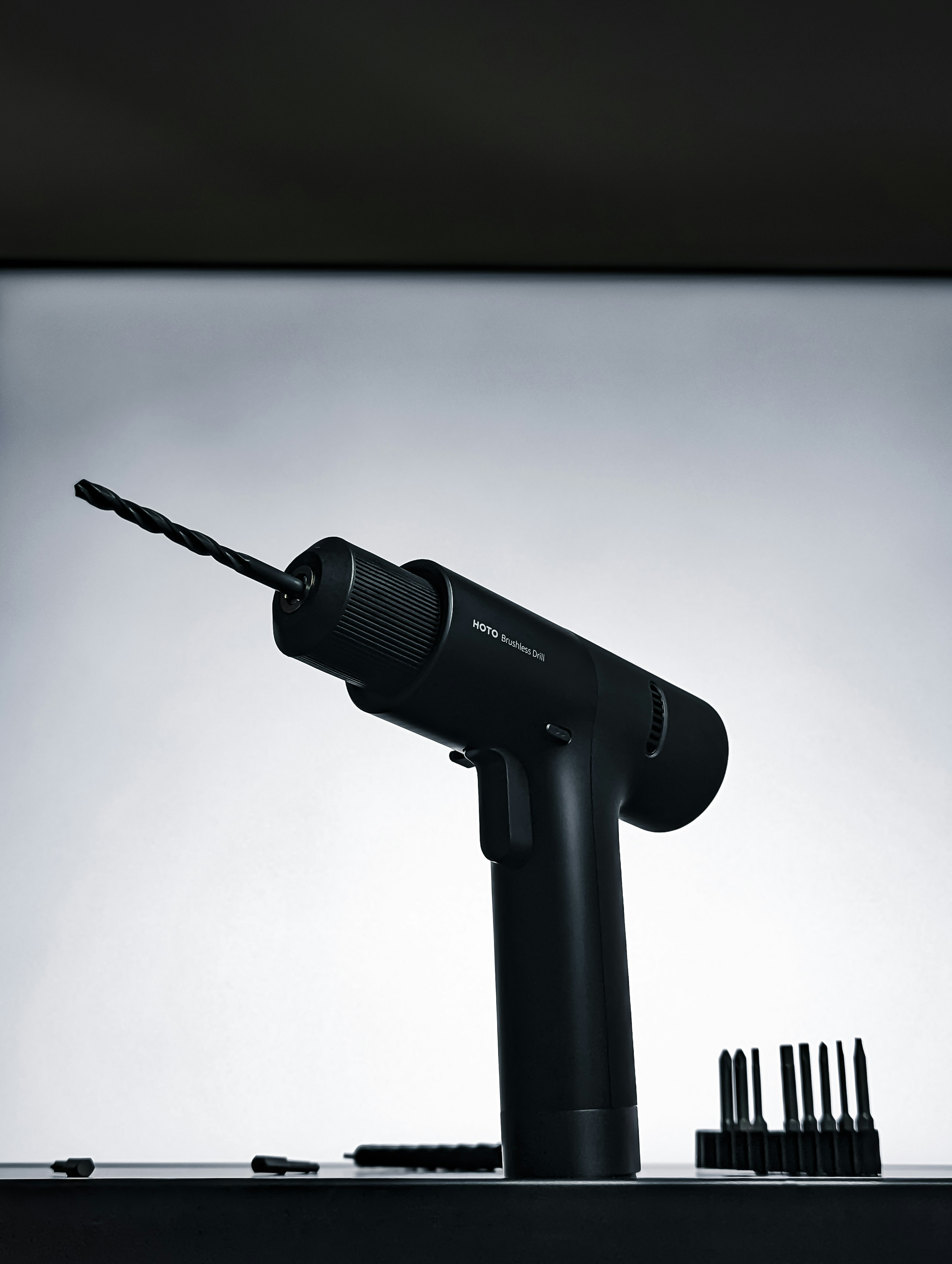 Sleek black drill positioned against a gradient background, showcasing its intricate design and accessories.