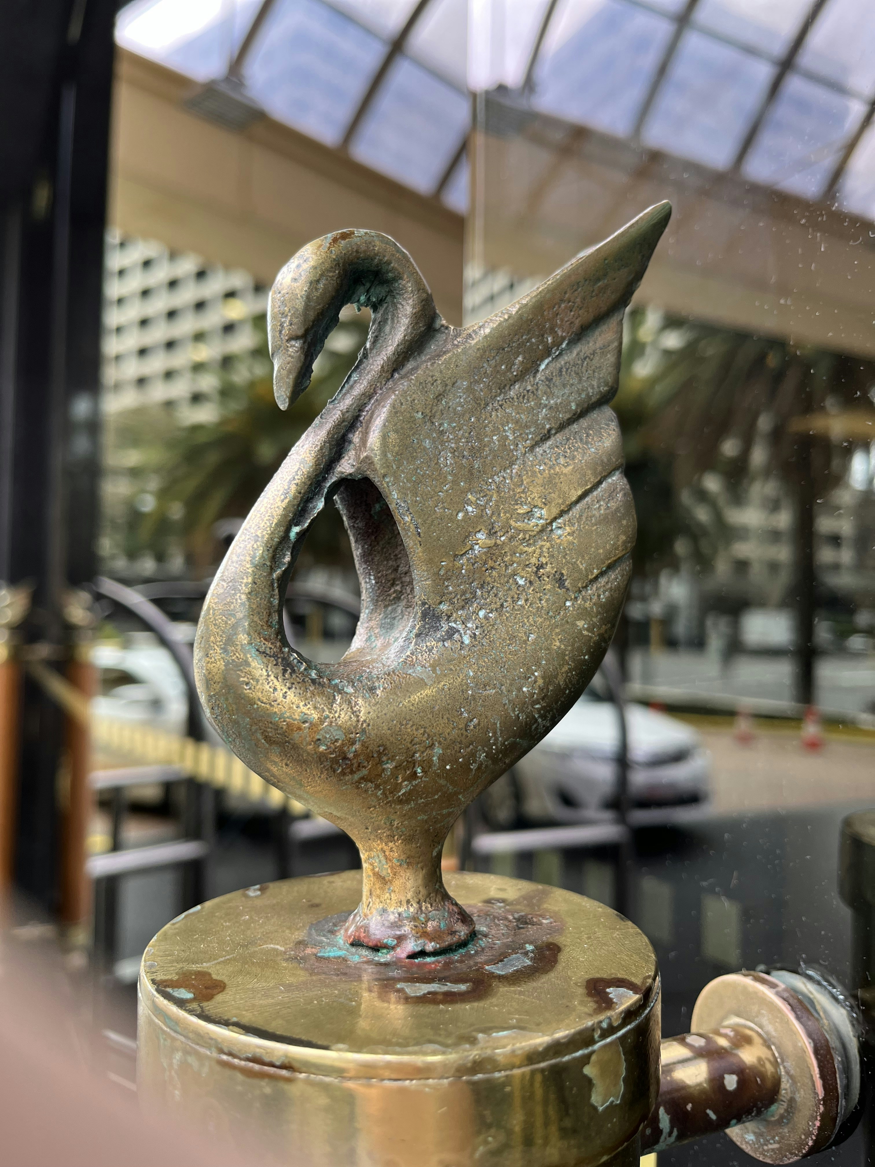 Patinaed Swan in the Atrium: Weathered Bronze with Glass Reflections