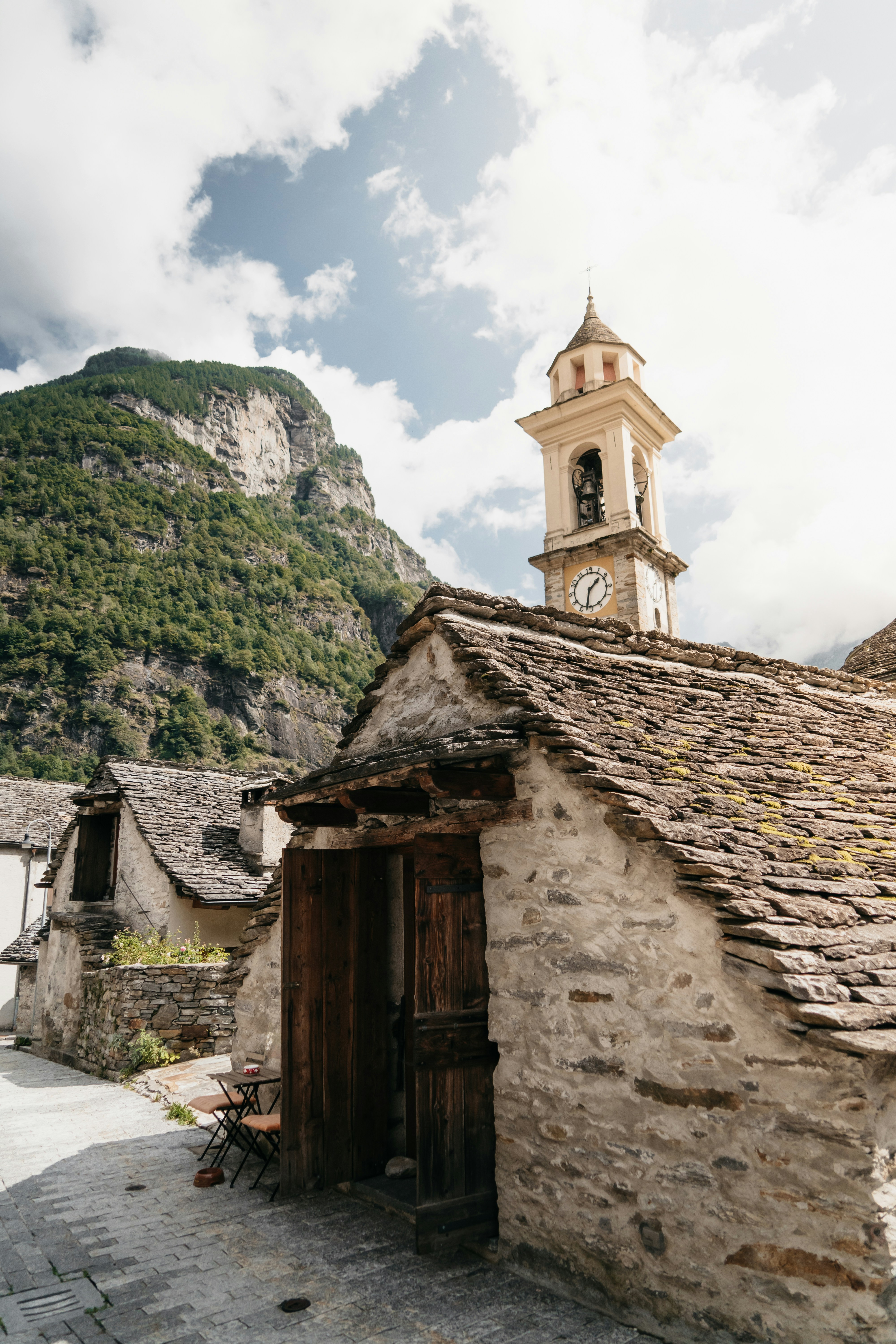 Clock Tower Above the Stone Village Against Alpine Backdrop