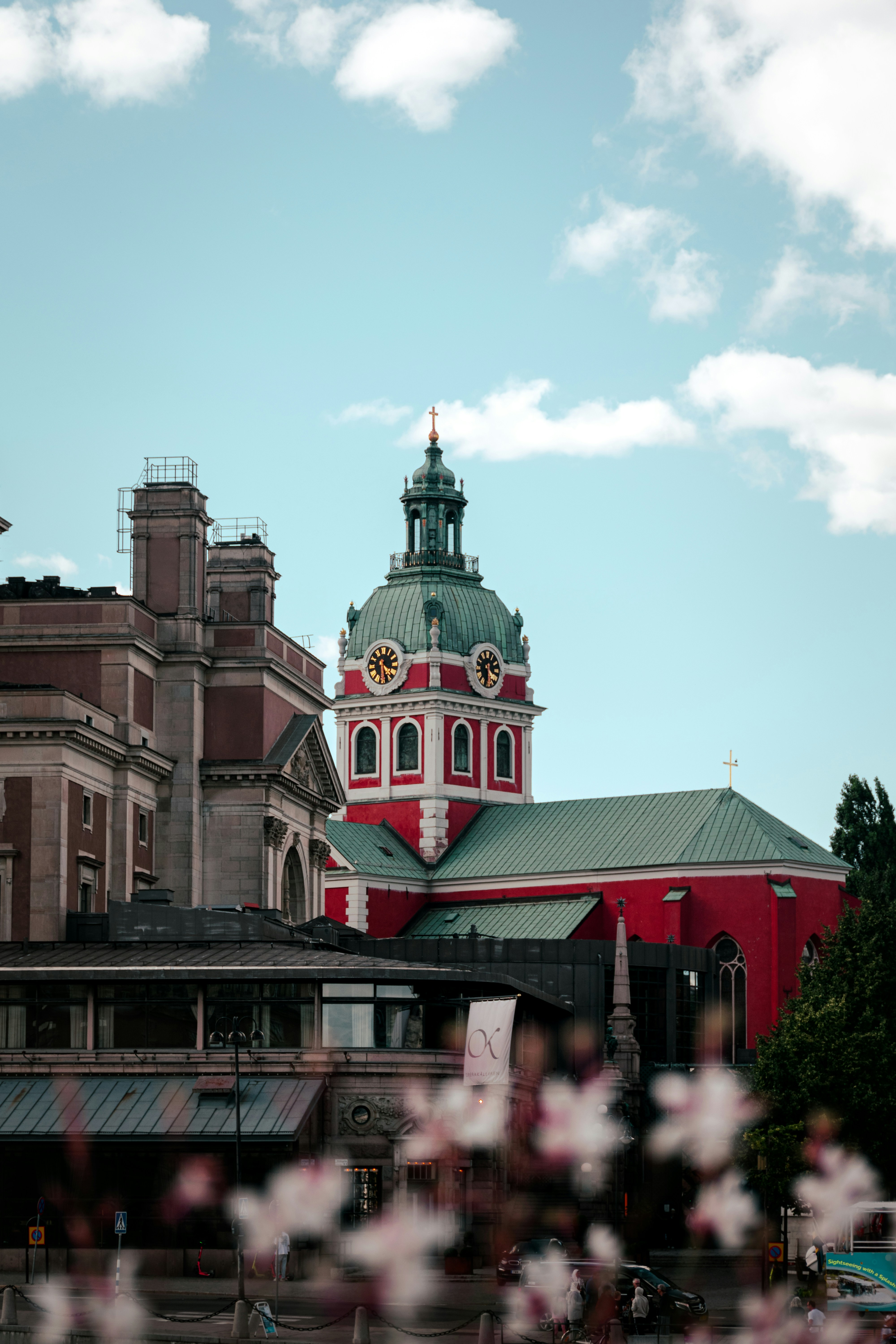 Green-Domed Clock Tower Rising Over a Red-Brick Cityscape