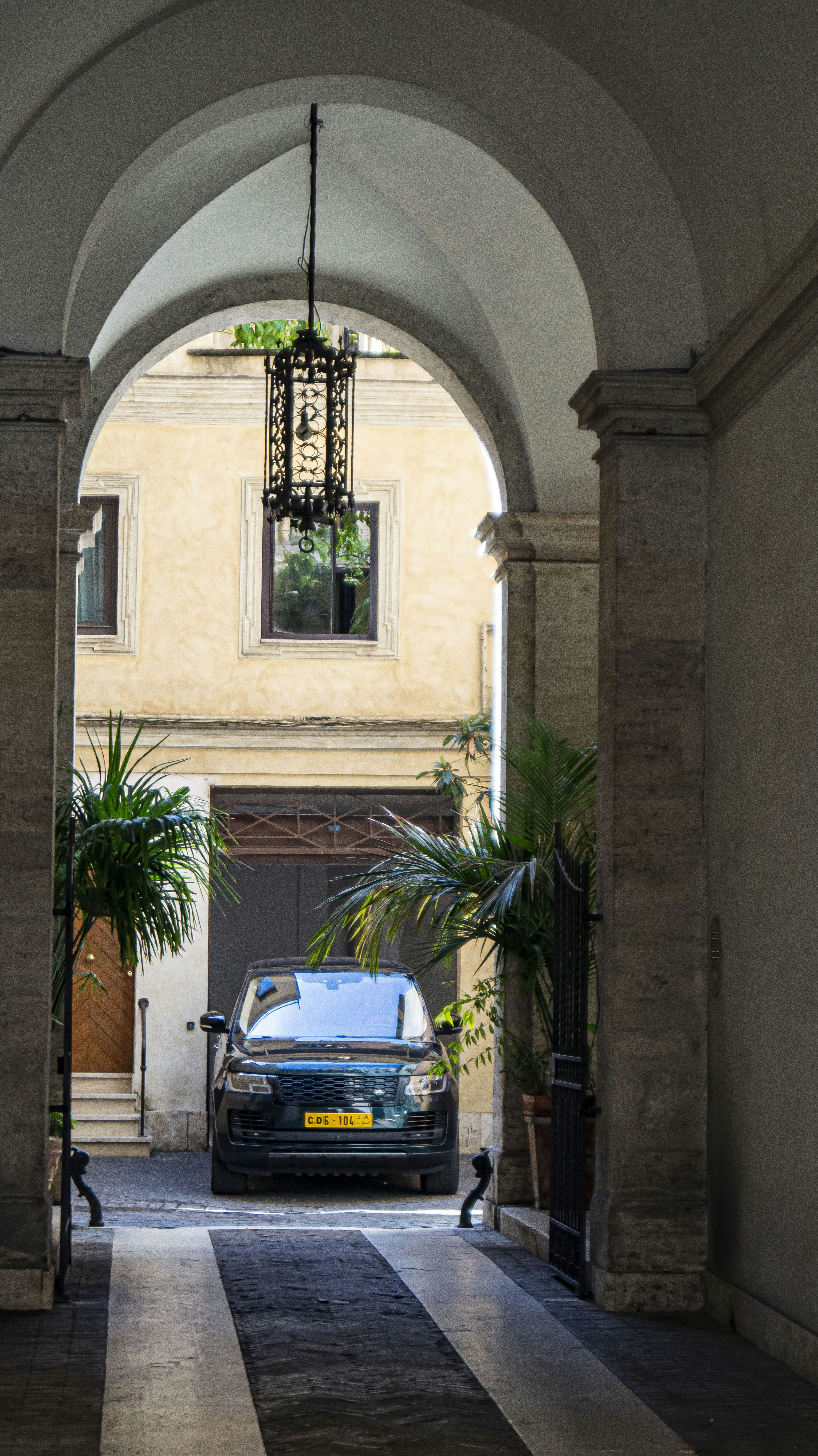 Gateway to the Carriage Courtyard: Sunlit Archway Framing a Black SUV
