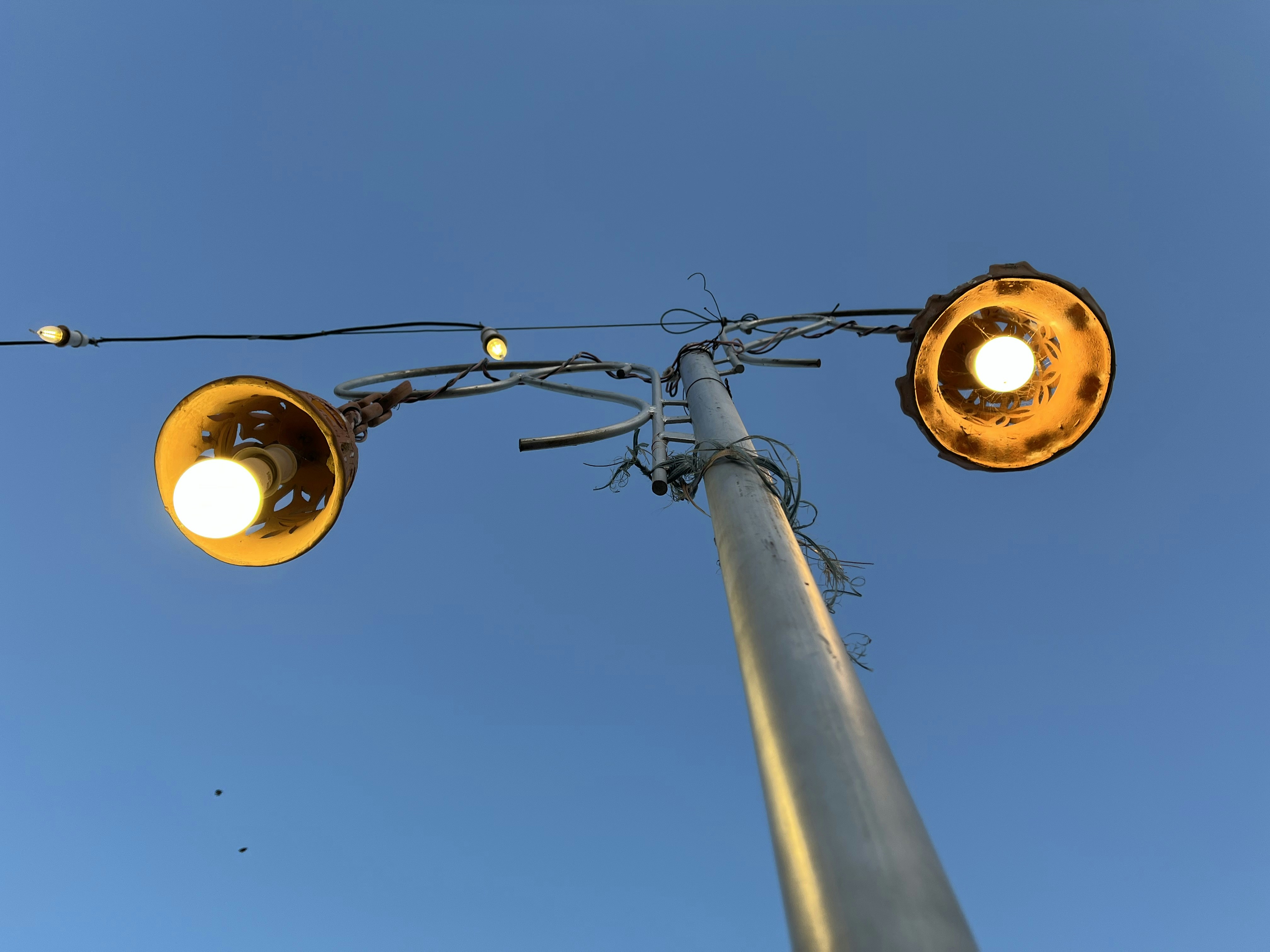 Amber Lanterns on a Weathered Pole Against a Clear Blue Sky