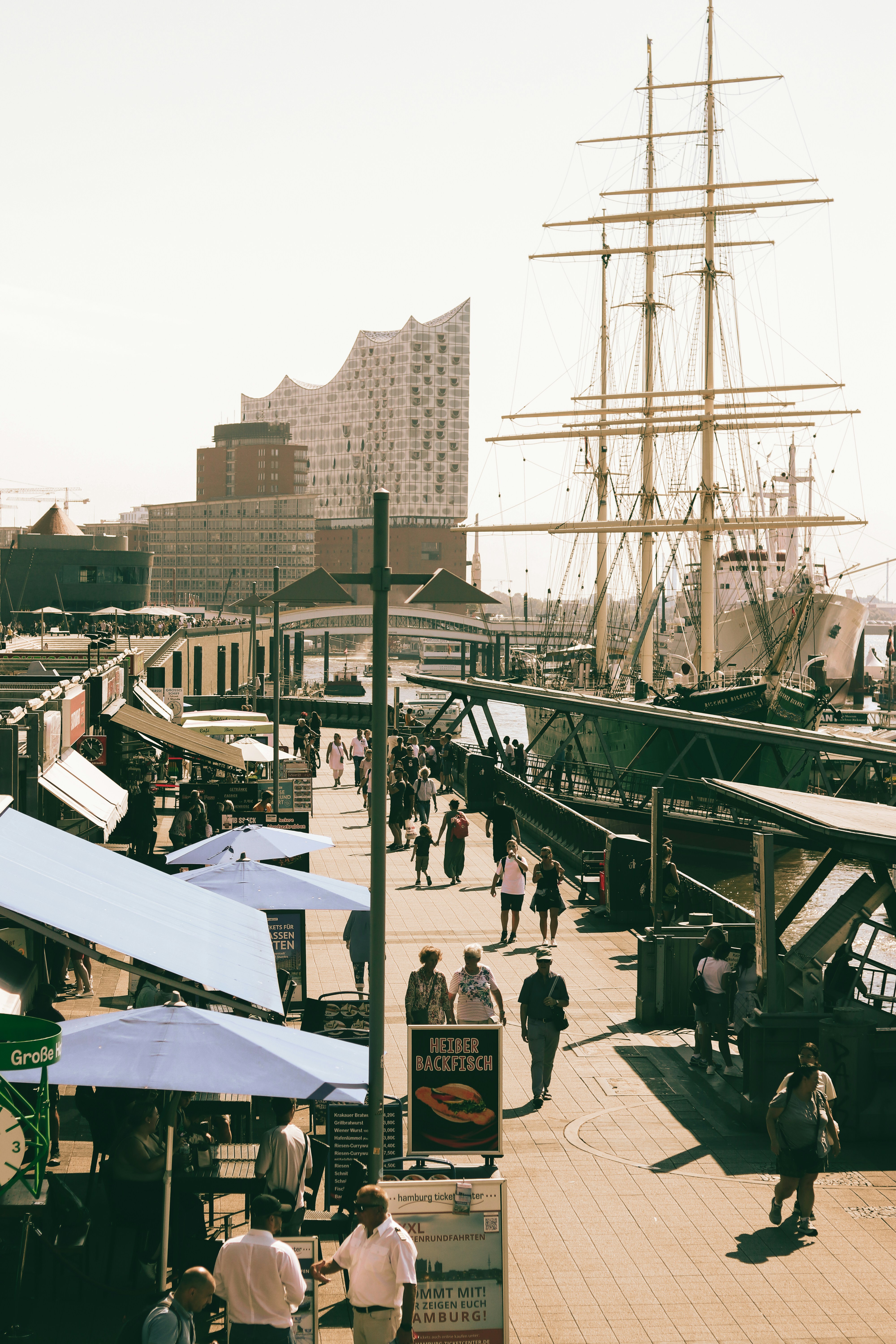 Harbor Promenade: Sailboats, Shaded Walkways, and Cityscape Reflections