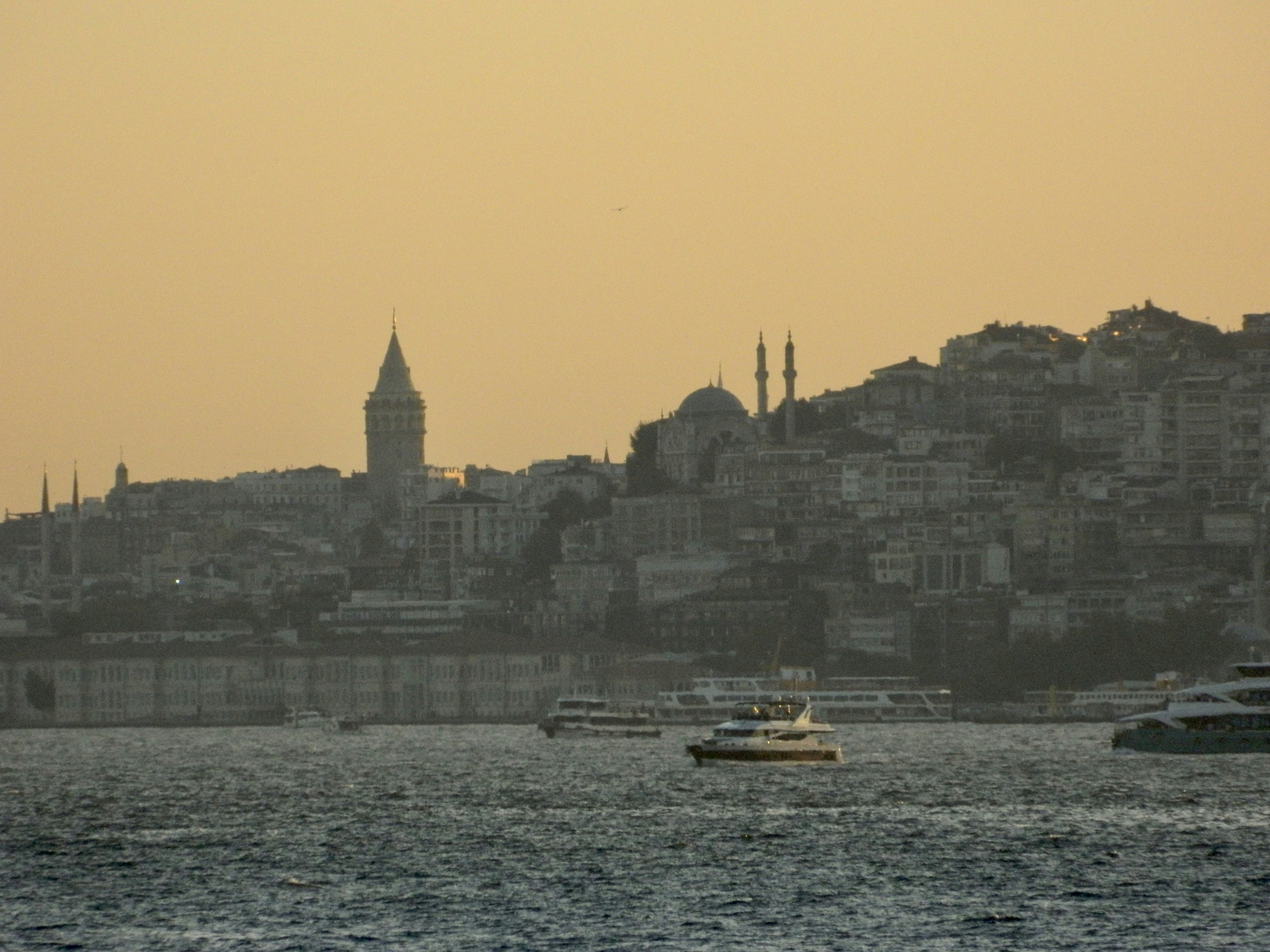 Silhouette of Istanbul's skyline with historic towers and mosques against a golden sunset sky over the Bosphorus.