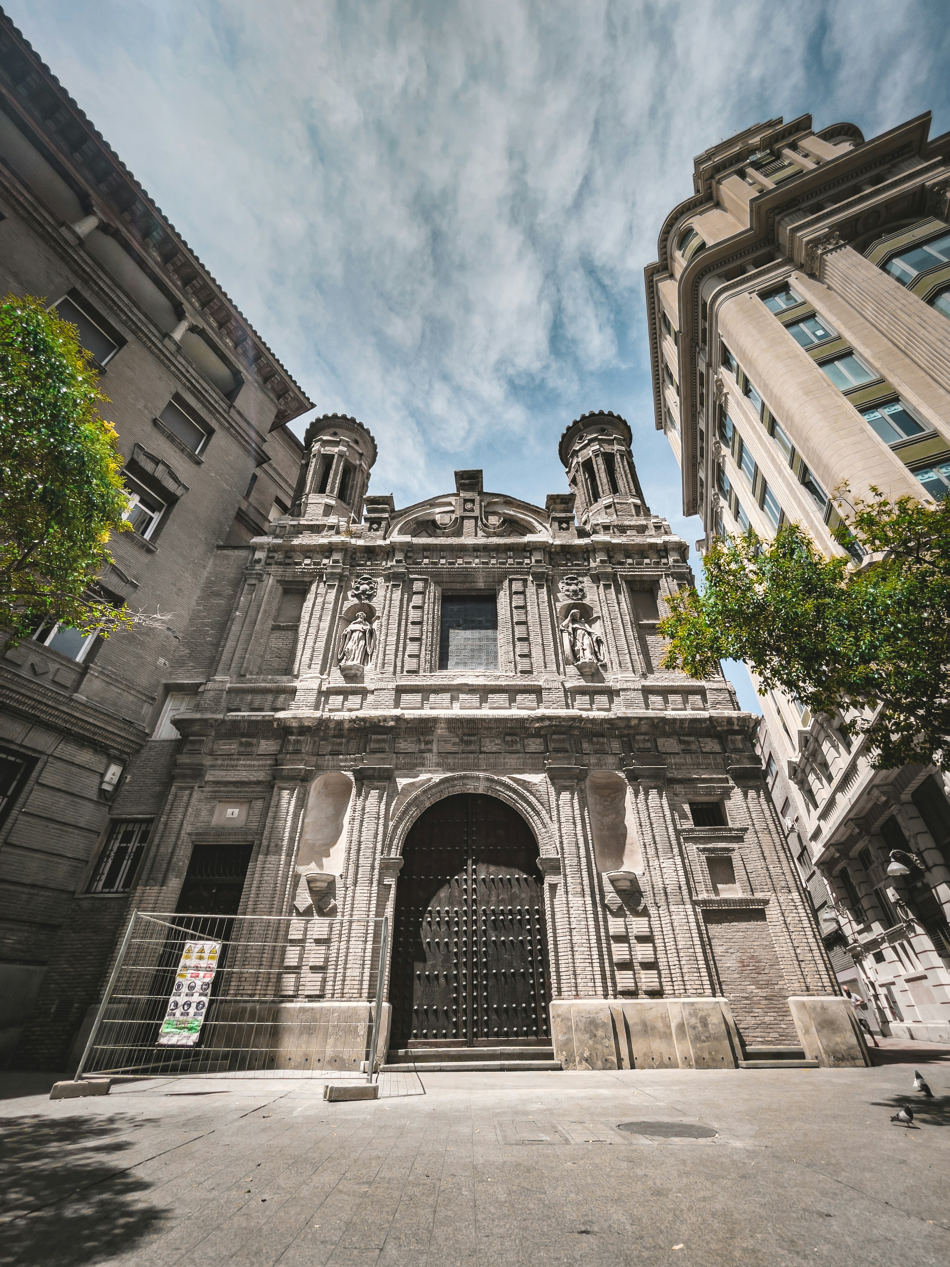 Portal Between Eras: A Baroque Facade Framed by Urban Giants
