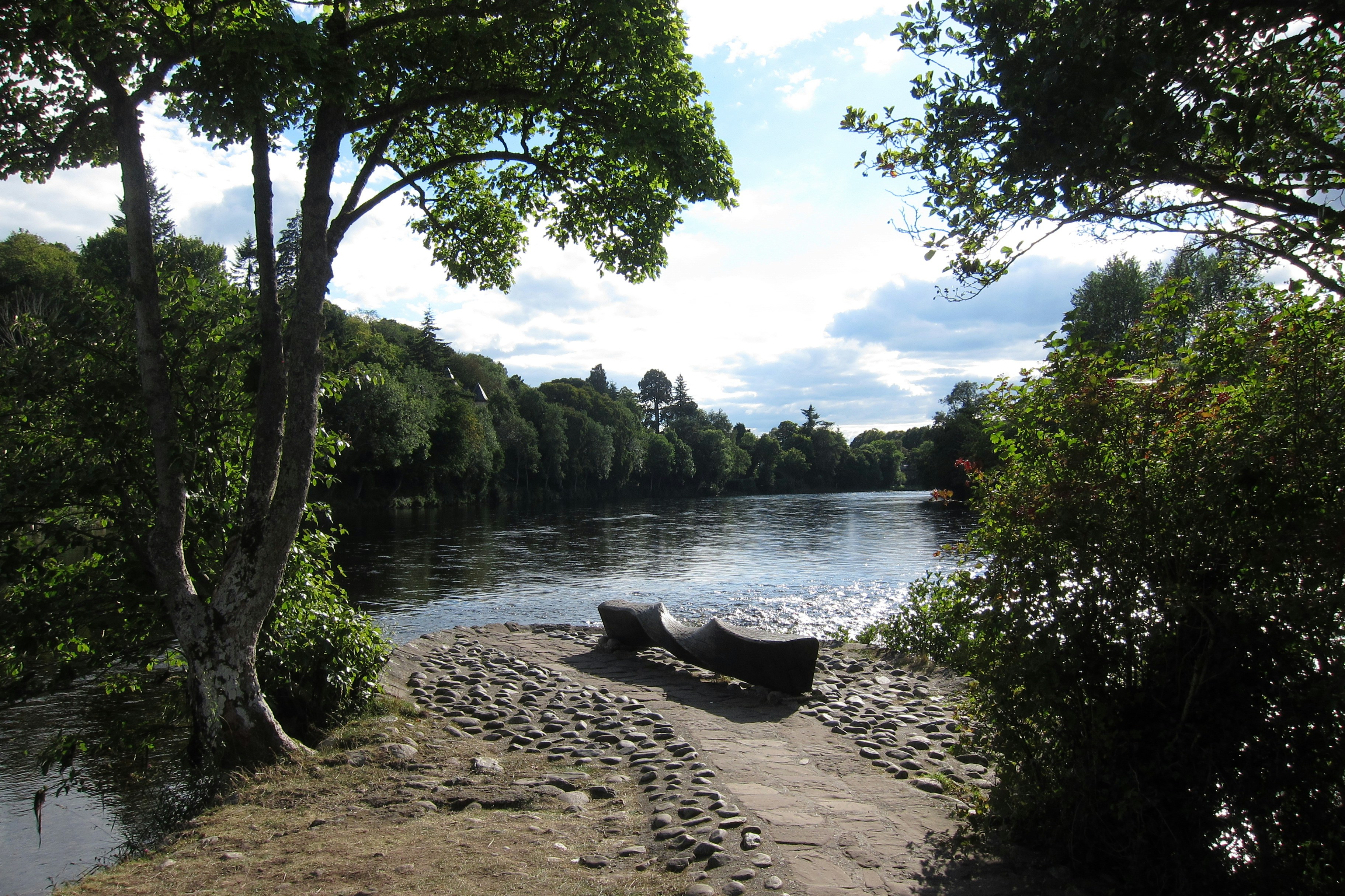 View from the tip of the Ness Islands in Inverness (Scotland) to the river Ness | a river with a boat on it