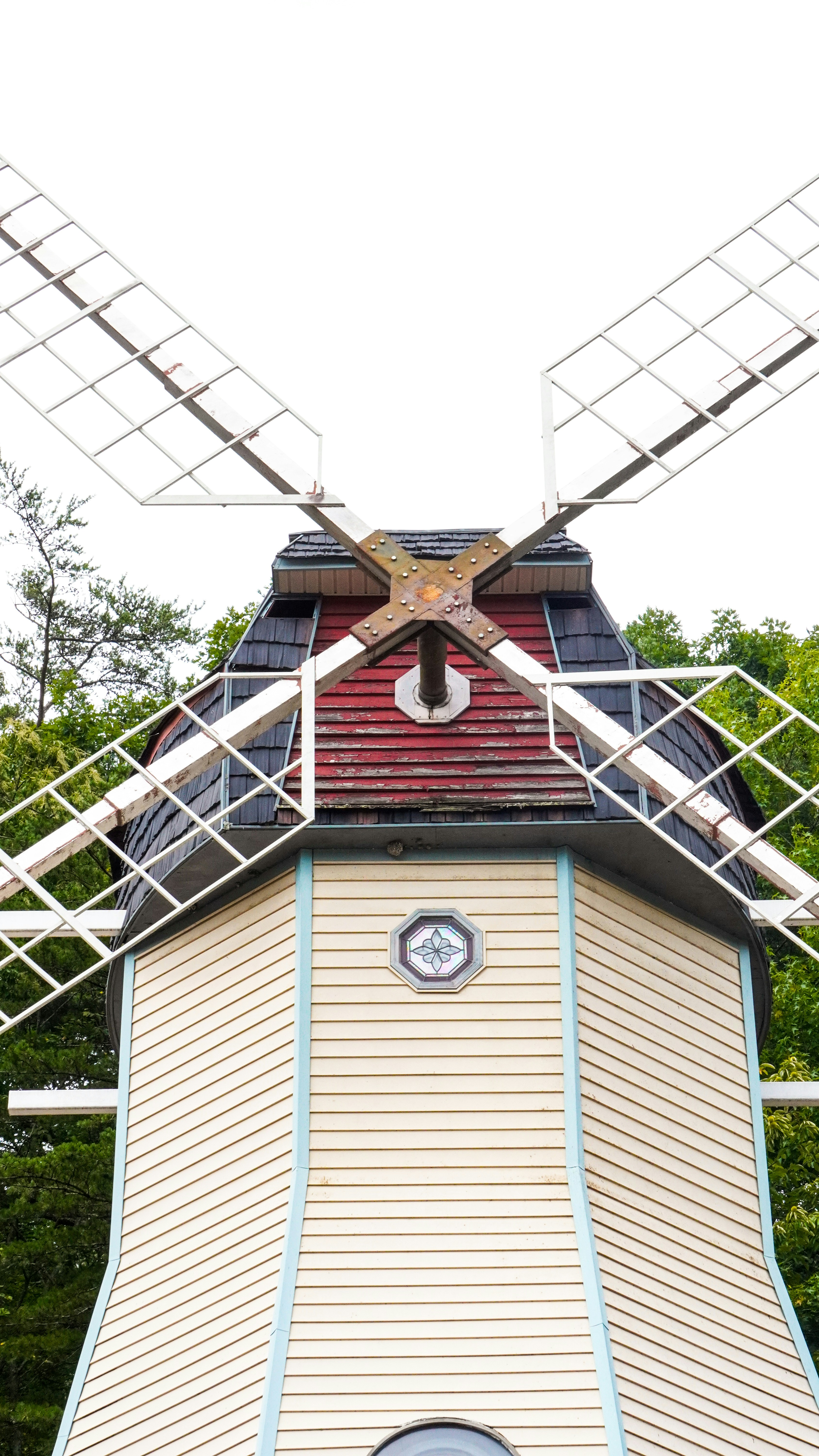Pastel Windmill Cross: Geometric Sails Framing a Timbered Tower