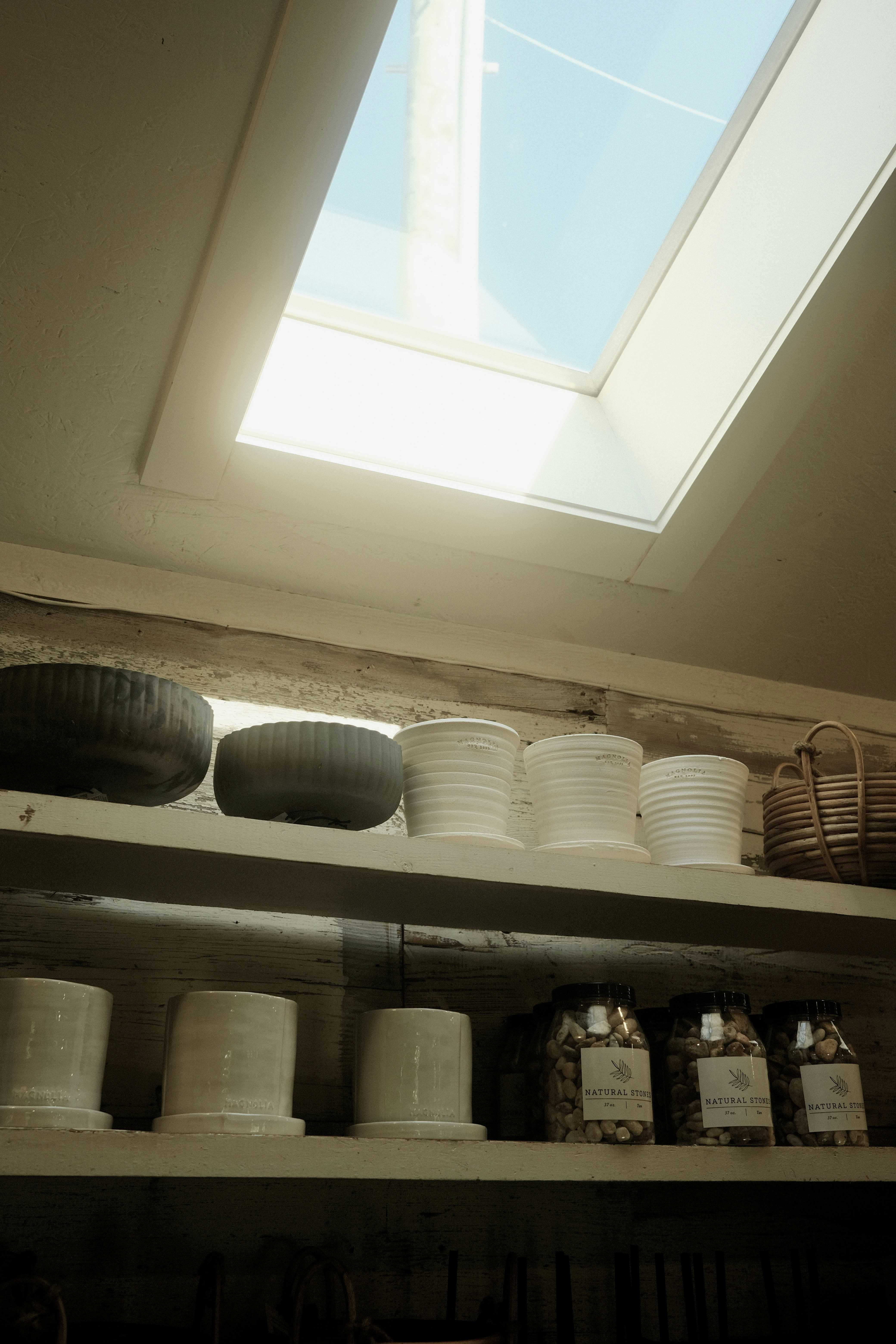 Sunlit Skylight Over Rustic Pantry Shelves of Ceramics