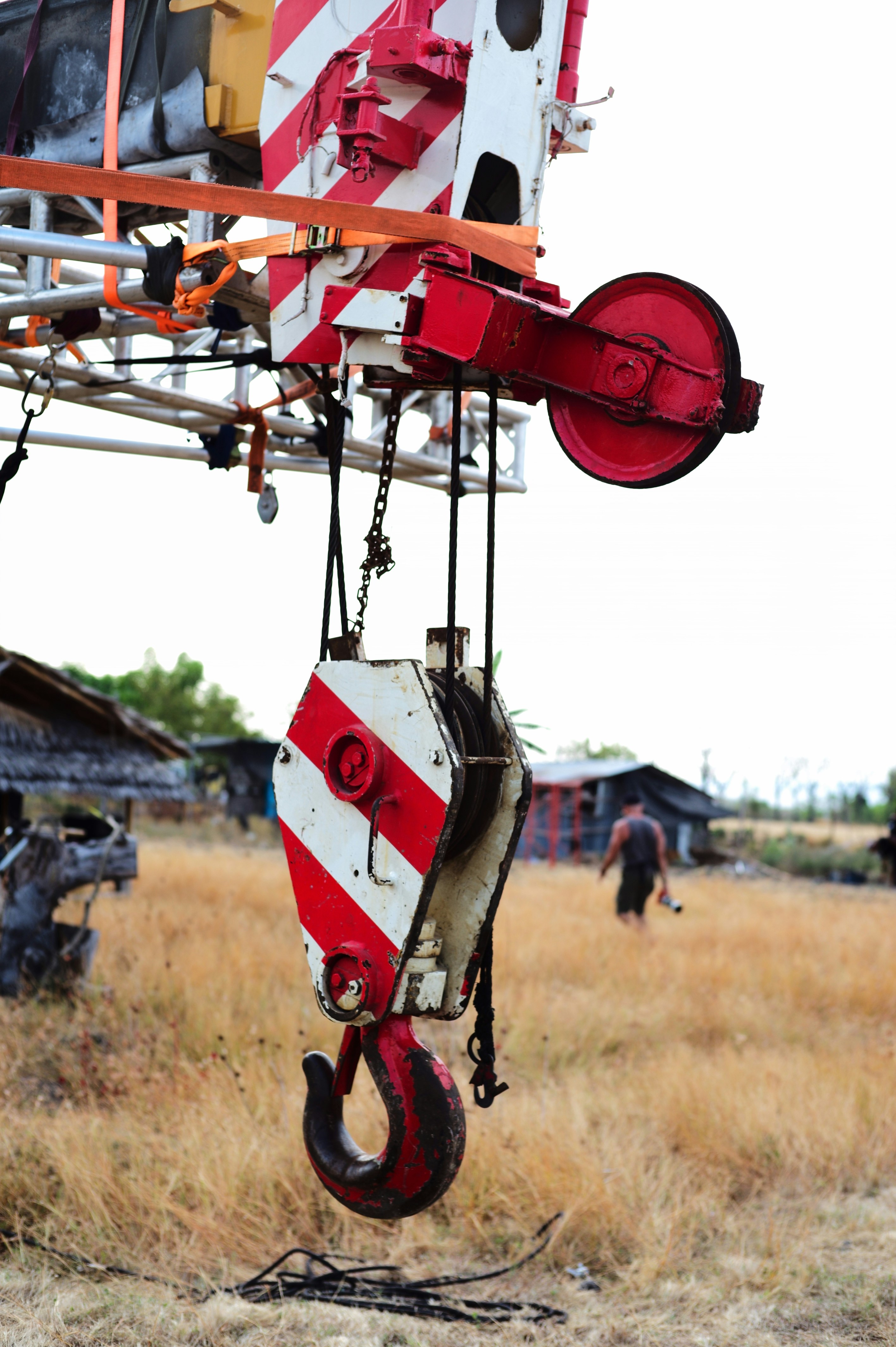 Red and White Industrial Crane Hook Grips a Scene of Desolate Fields