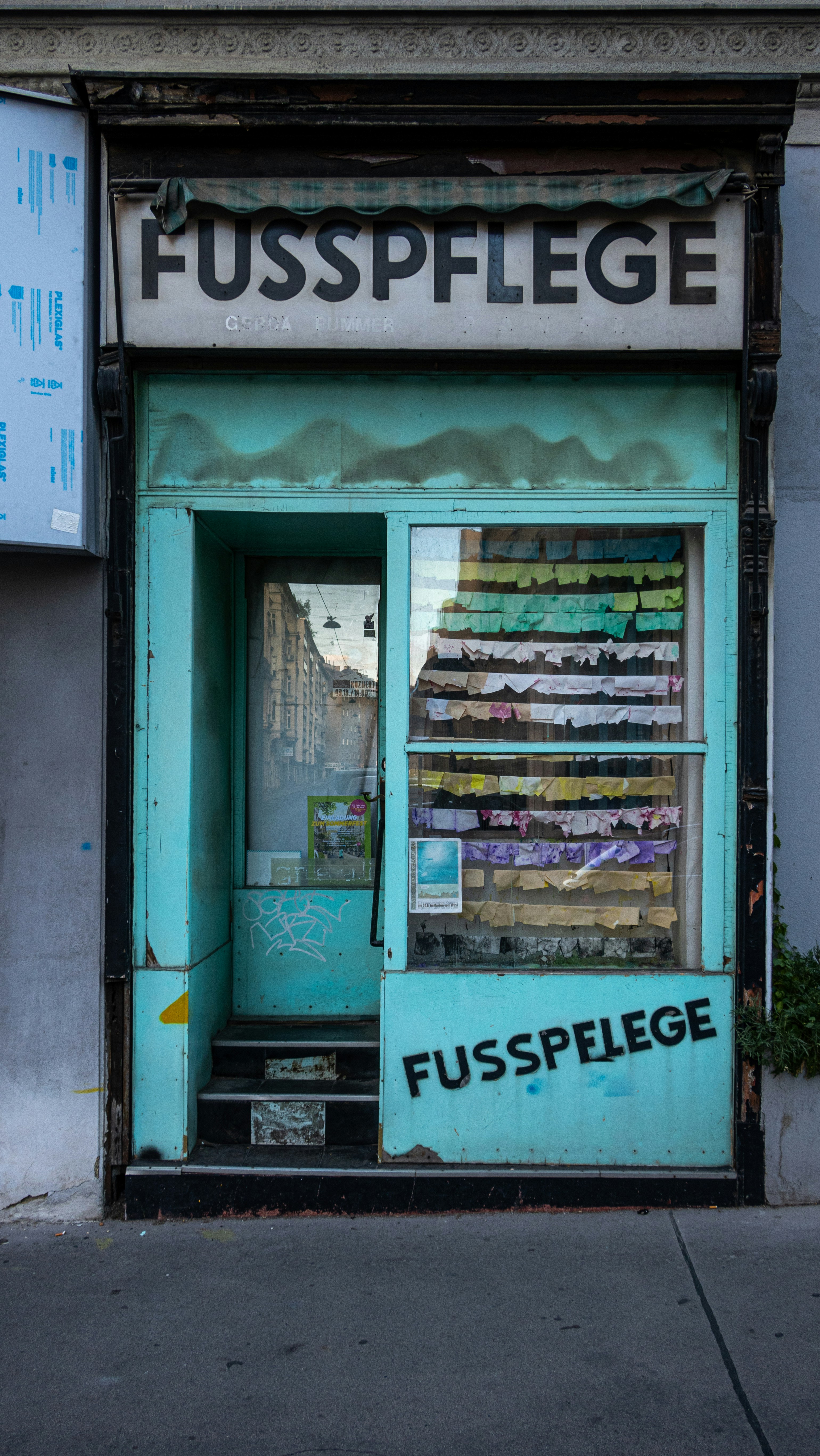 Minty turquoise storefront of a nail/foot care shop with stacked papers