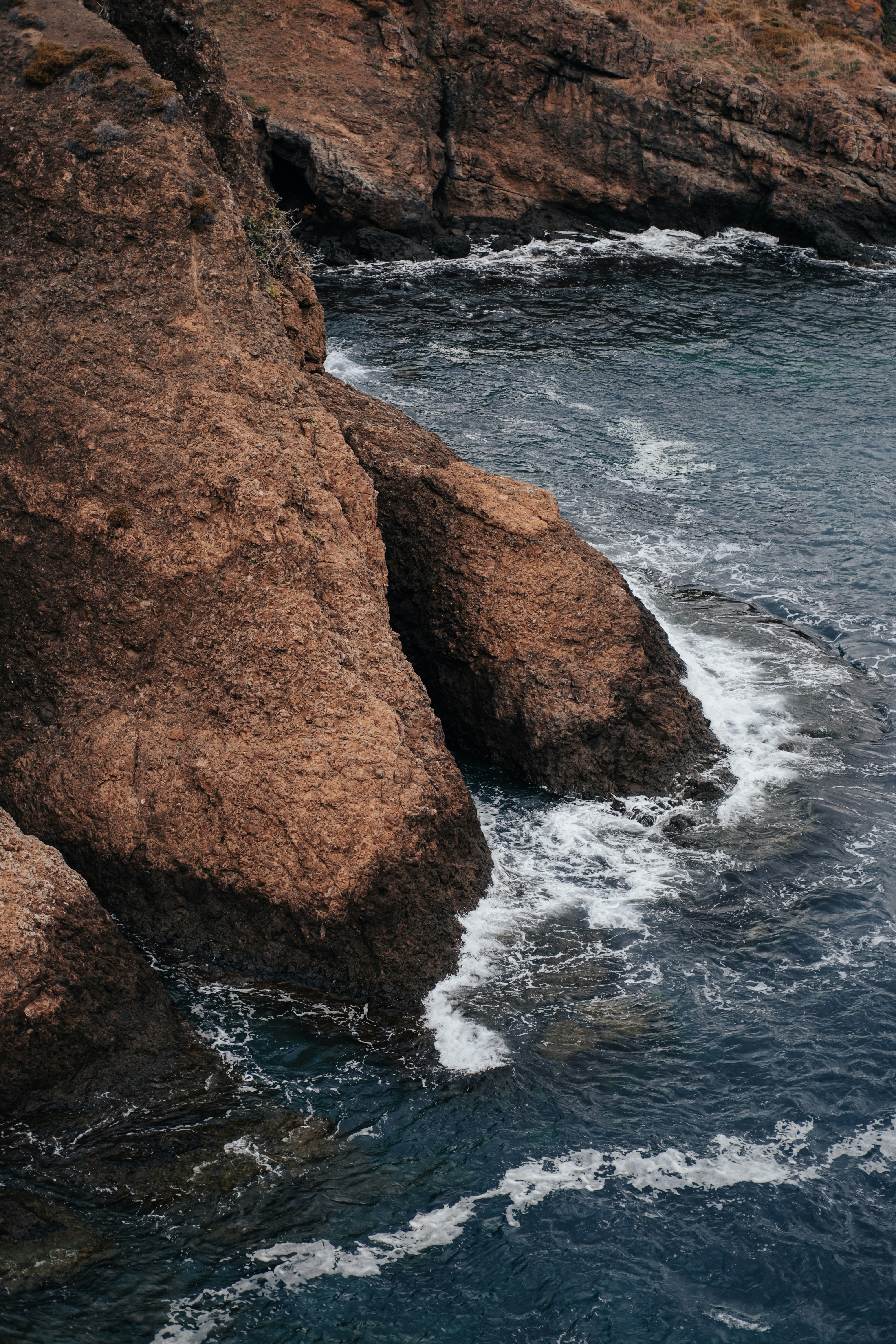 Foto Un acantilado rocoso junto a un cuerpo de agua – Imagen Gris ...