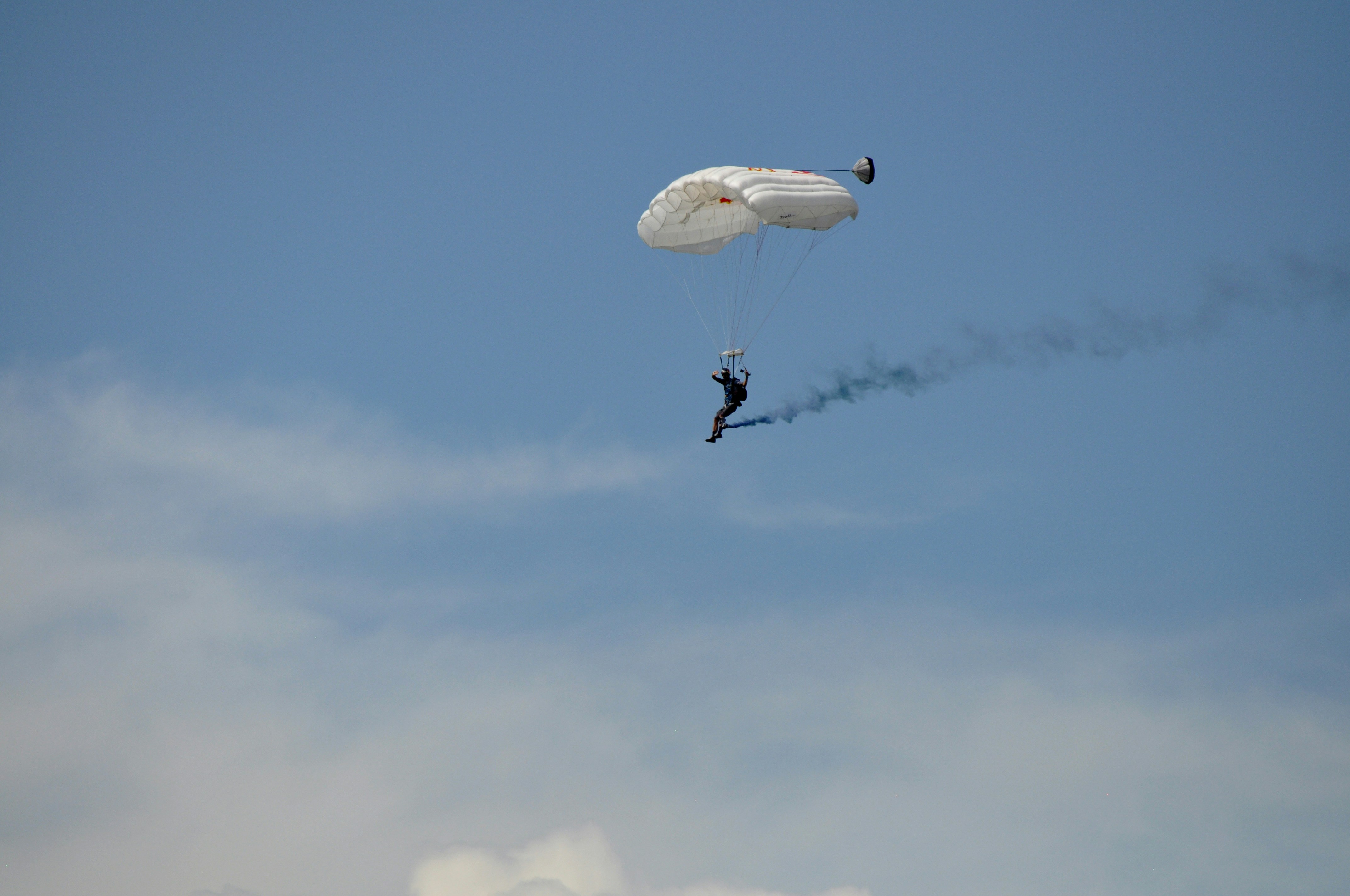 Freefall and Flight: A Parachutist Traces a White Arc Across a Clear Sky