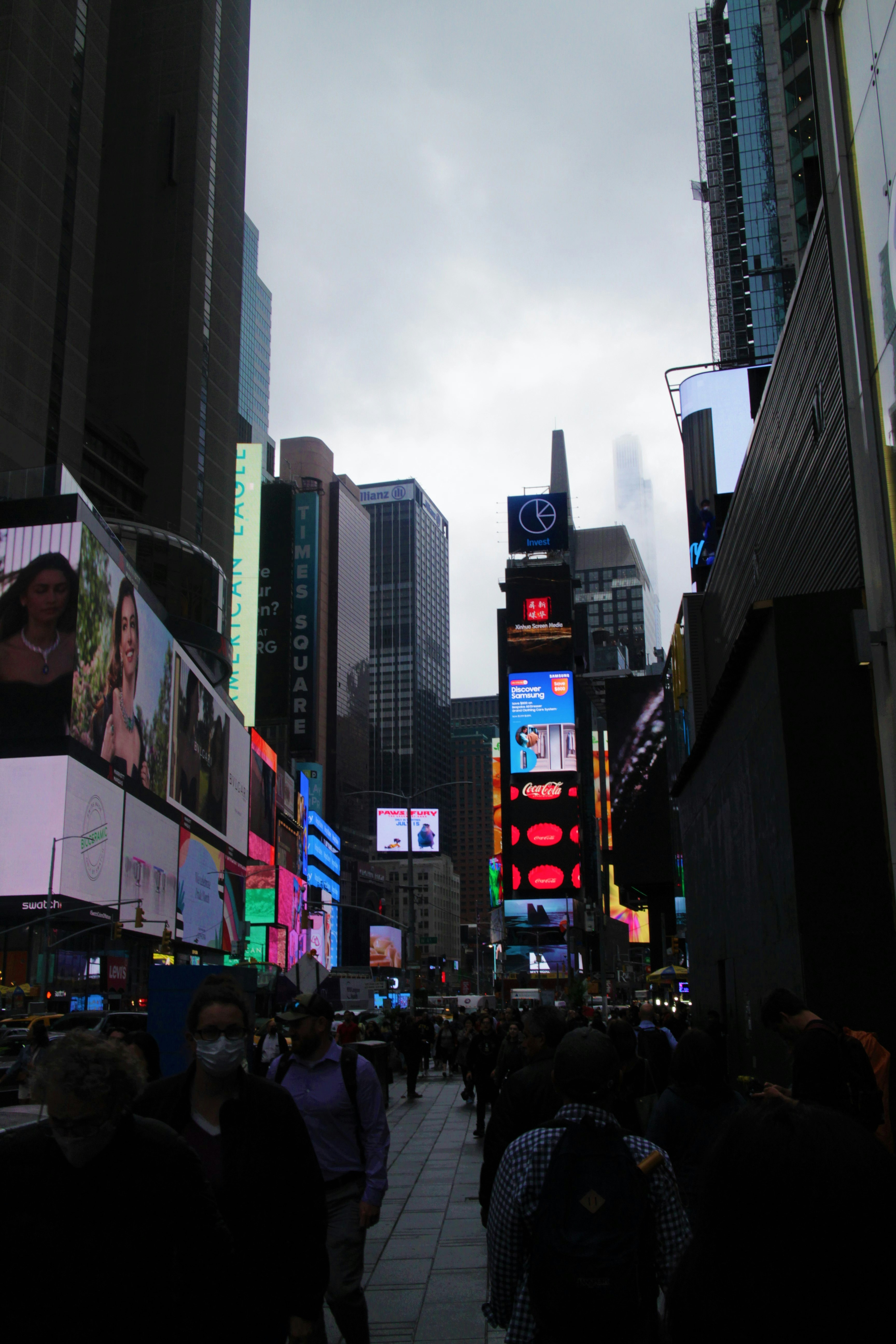 Photograph of Times Square at dusk, featuring towering neon billboards and a crowded pedestrian plaza.