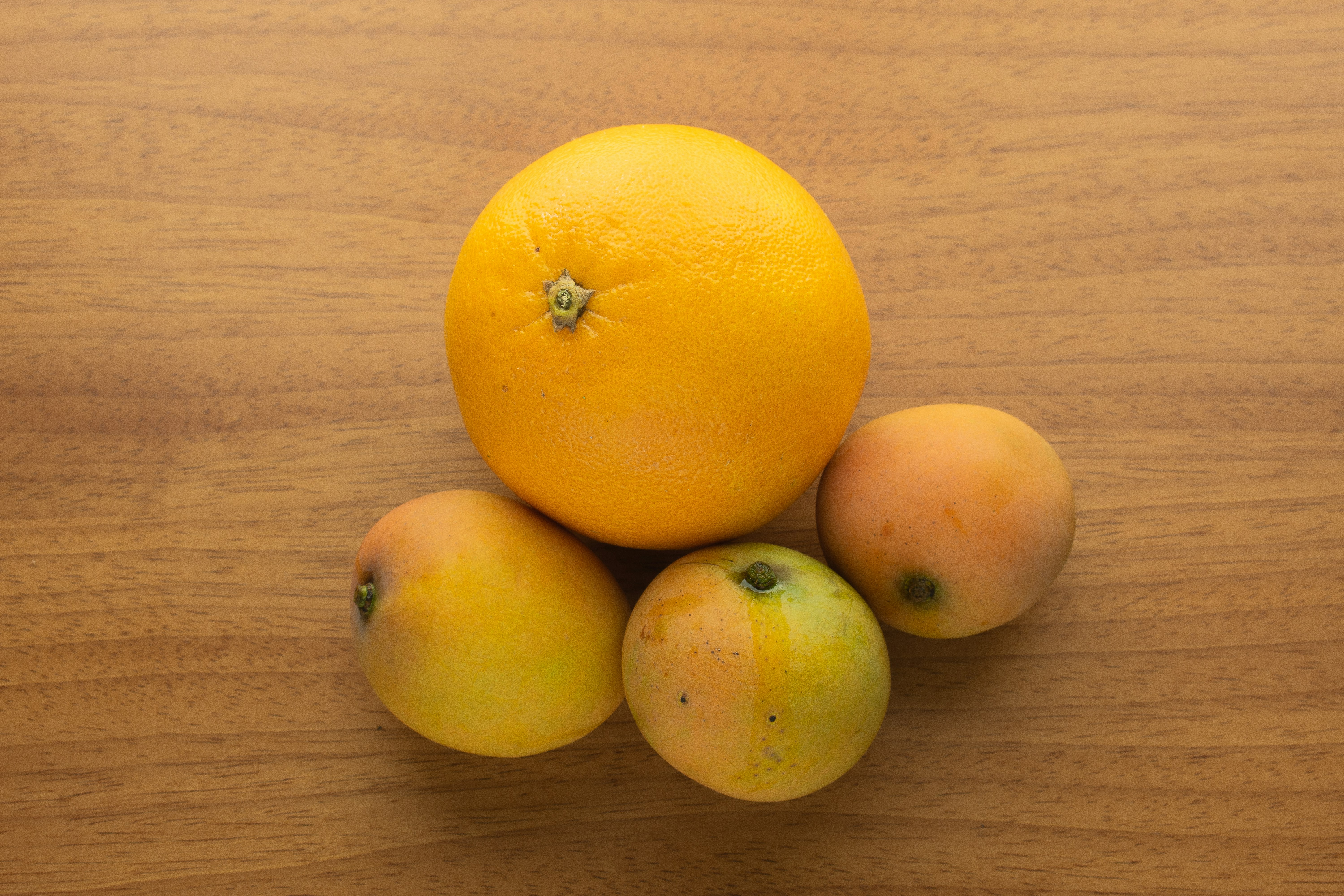 A vibrant arrangement of citrus fruits on a wooden surface, showcasing various sizes and shades of yellow and orange. The composition emphasizes their natural textures and colors.