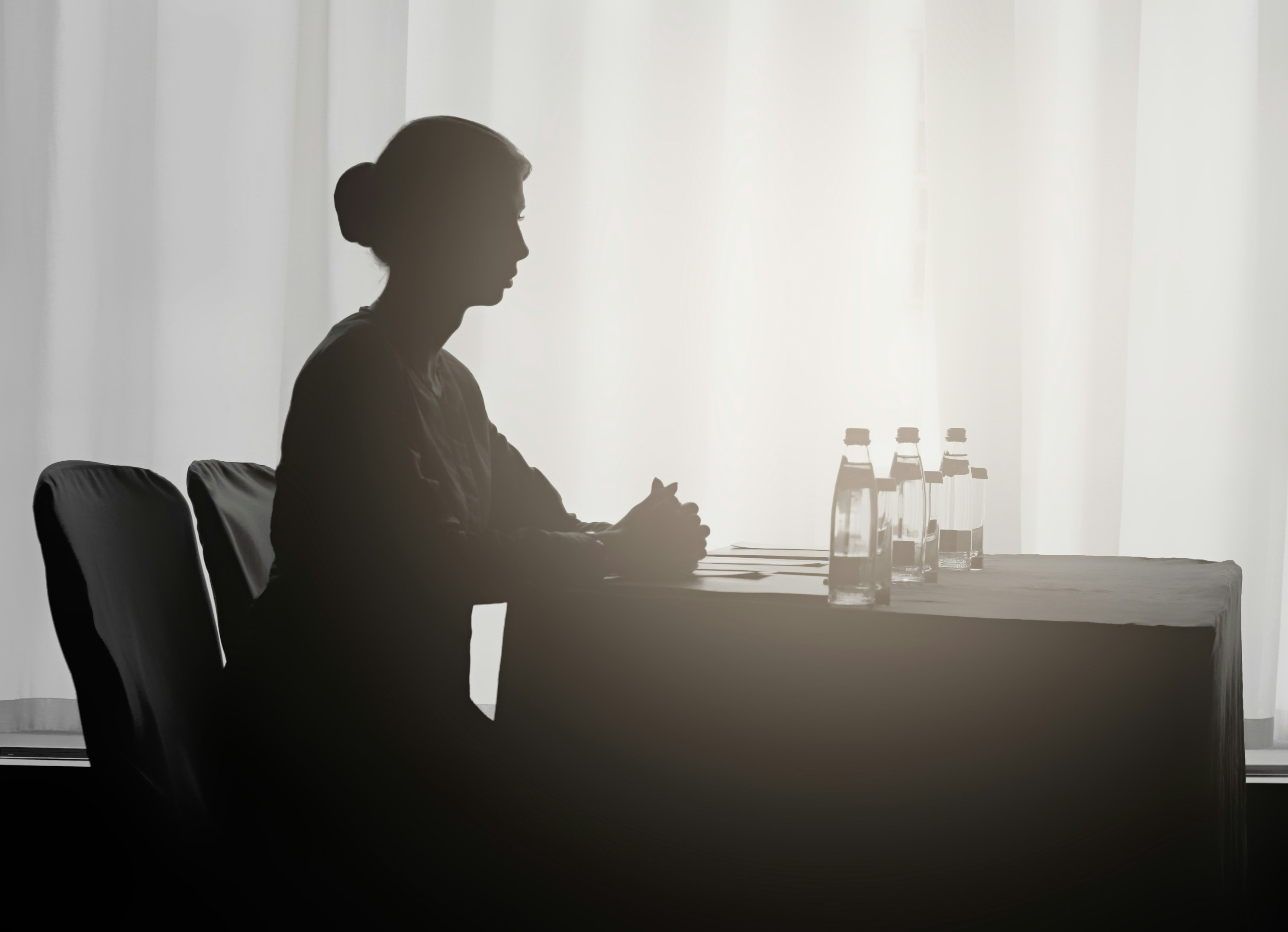 Silhouette at the Meeting: Quiet Moment Beneath Backlit Curtains