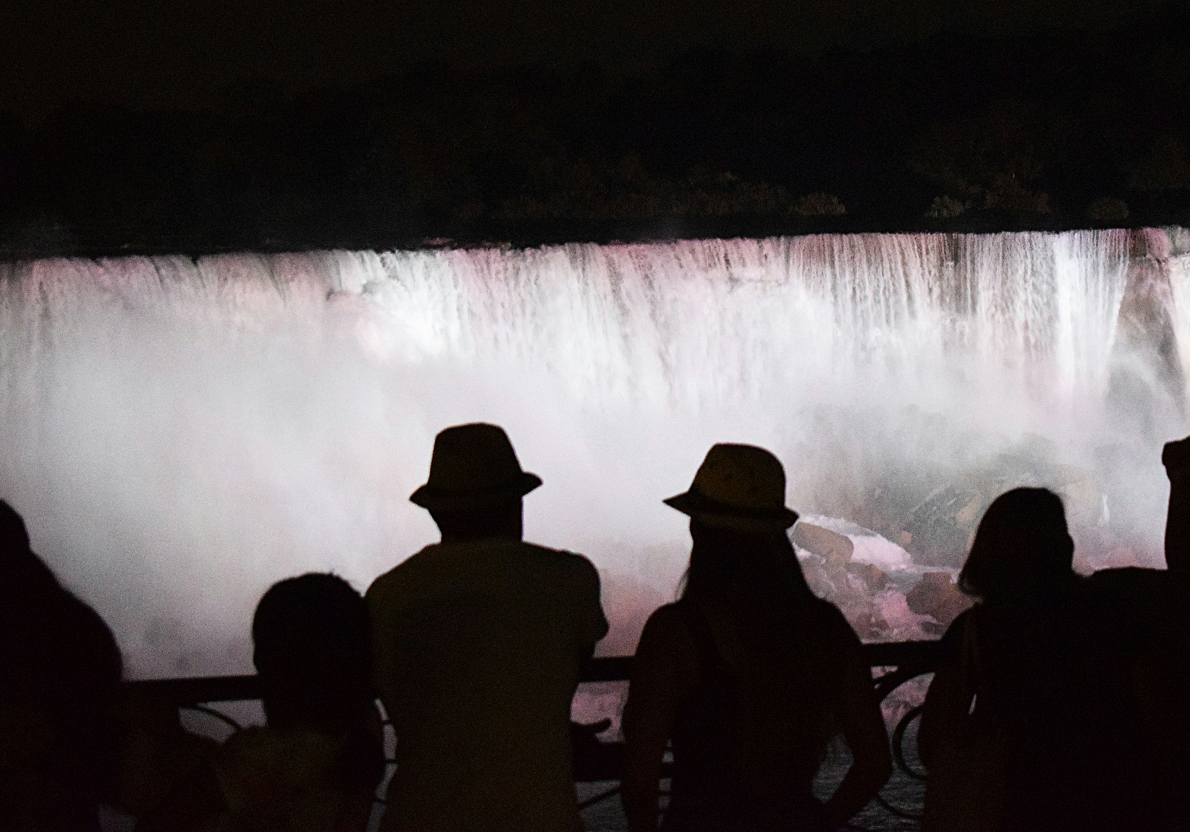Rim-View at Night: Silhouettes Observe the Illuminated Falls