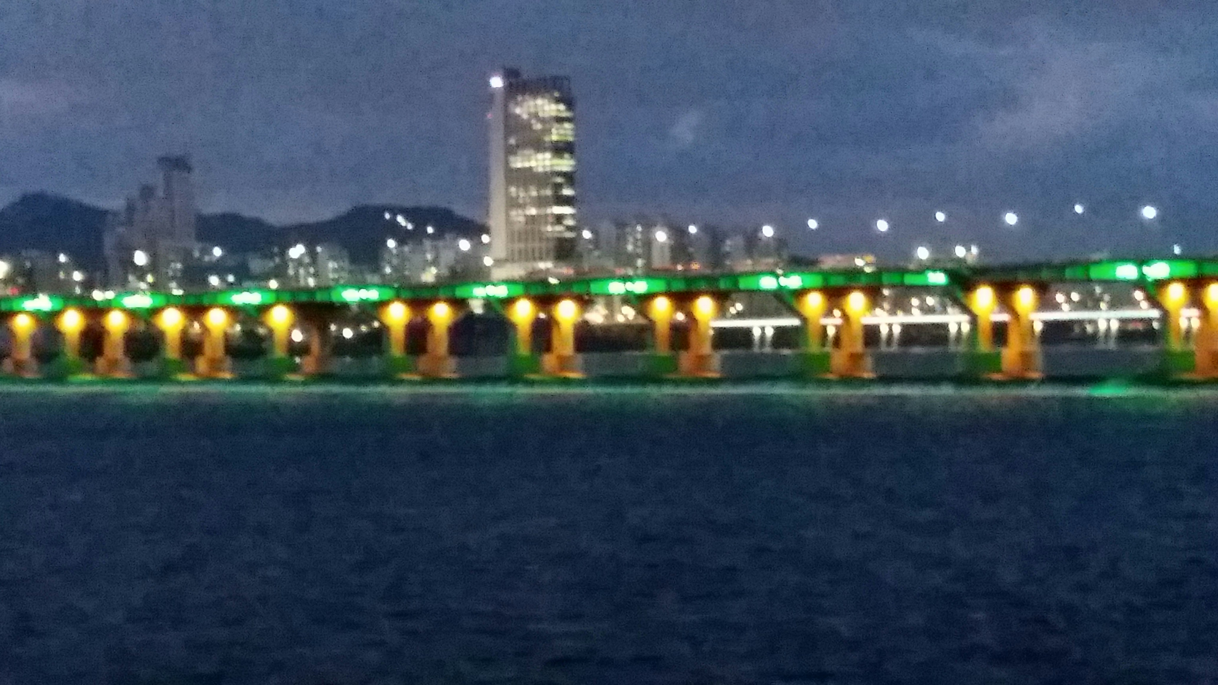 Neon Arc Over the River: Nighttime Bridge Lights and City Silhouettes