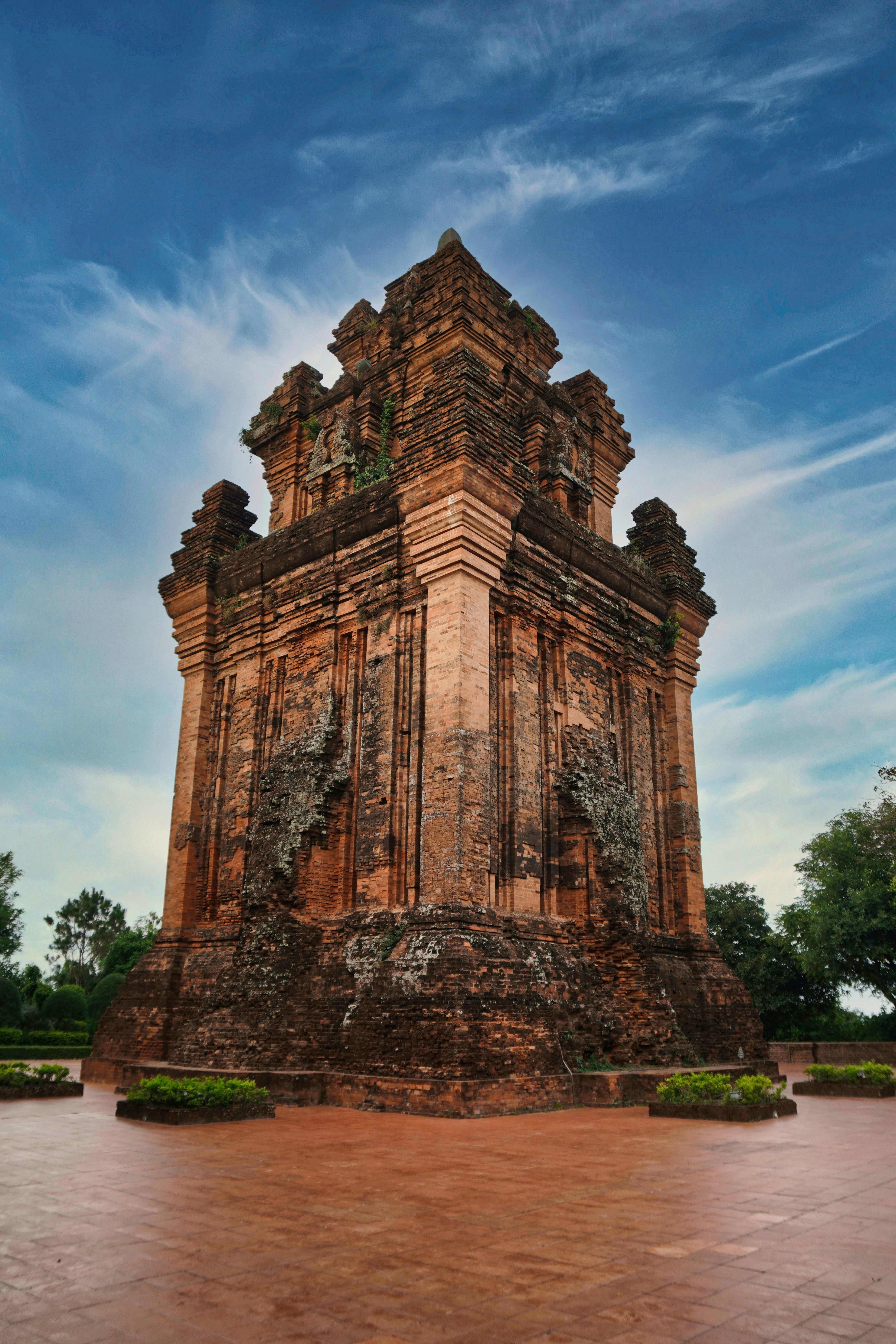 Brick Sentinel in a Sunlit Plaza: An Ancient Tower Reaches Toward a Cerulean Sky