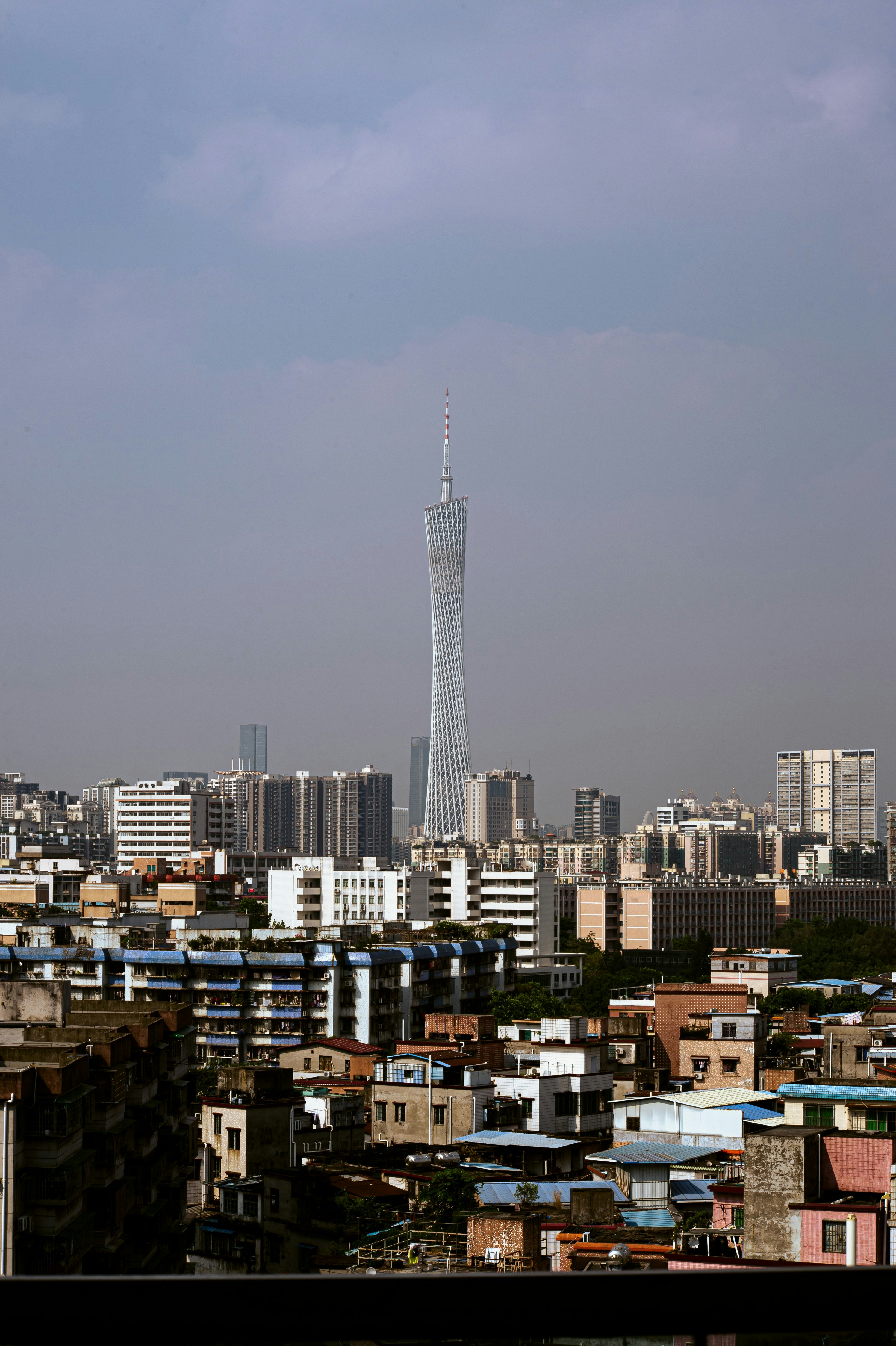 A panoramic view of a bustling cityscape featuring a prominent tower amidst a sea of residential buildings. The urban environment reflects the blend of modern architecture and everyday life.