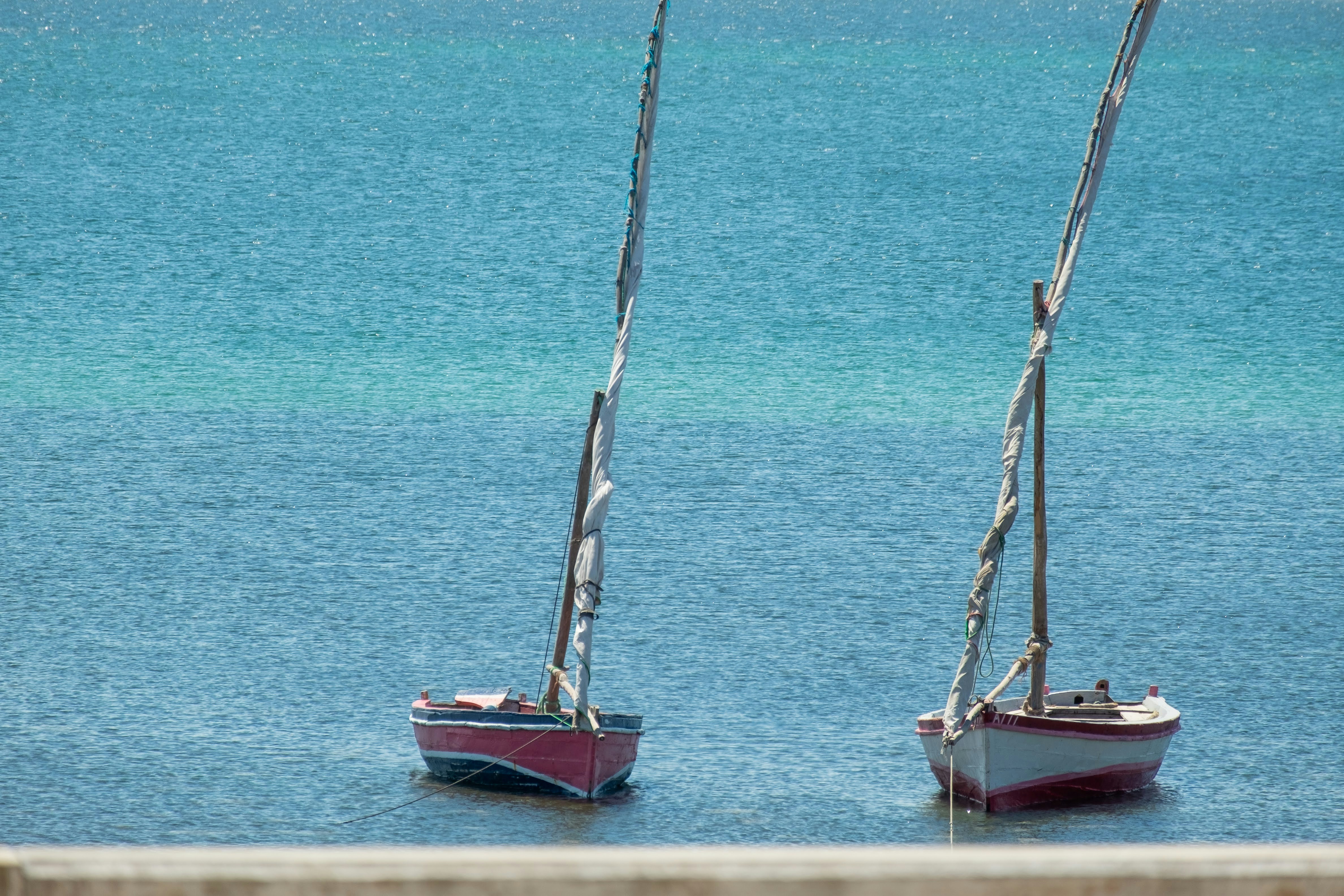 Two Red Sailboats Rest at Calm Blue Harbor