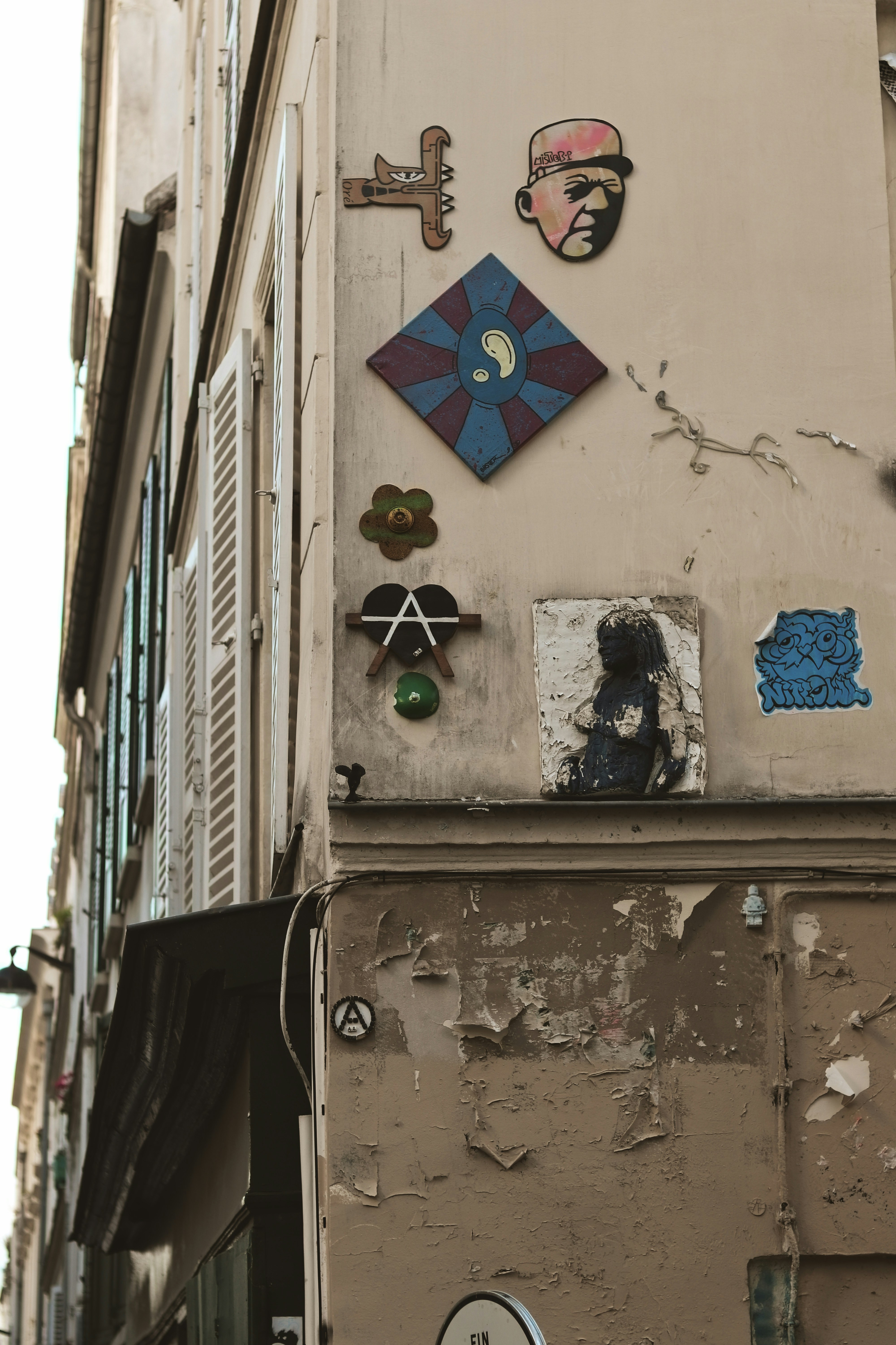 Stickered Facade: A Quiet Corner of Urban Graffiti on a Weathered Wall