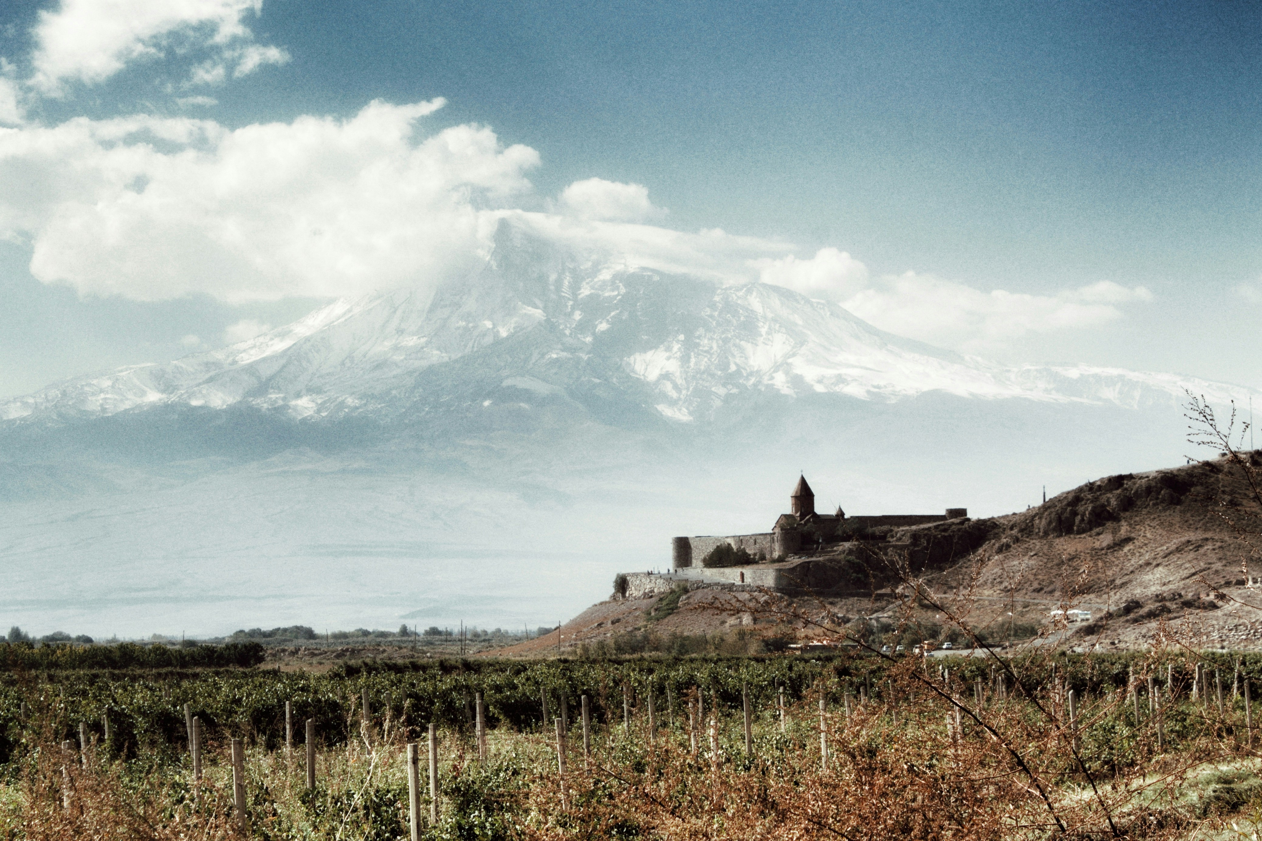 Fortress on a sunlit hillside beneath a snow-dusted Alpine panorama