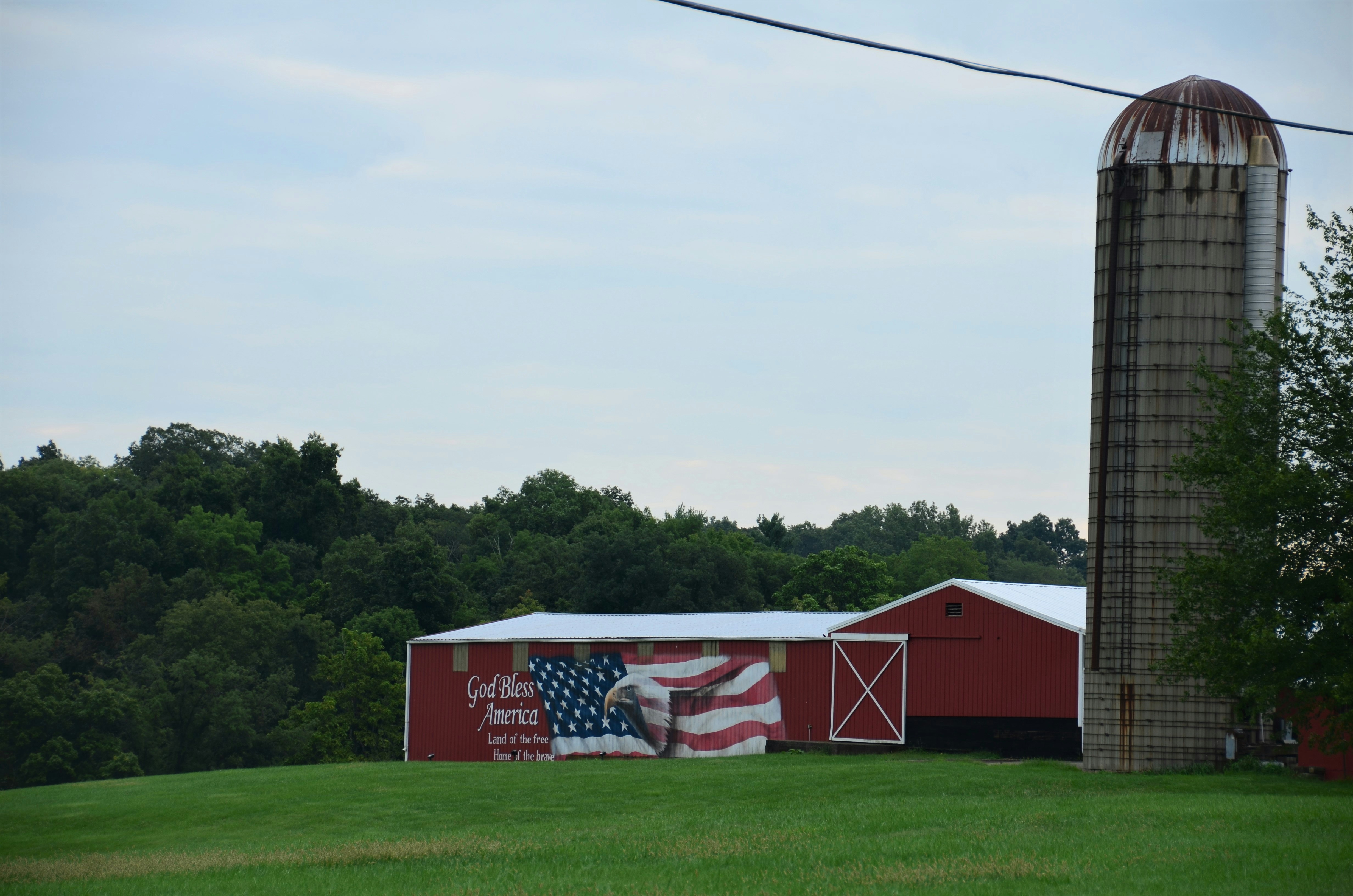 Red Barn with American Flag Mural Beside a Weathered Silhouette