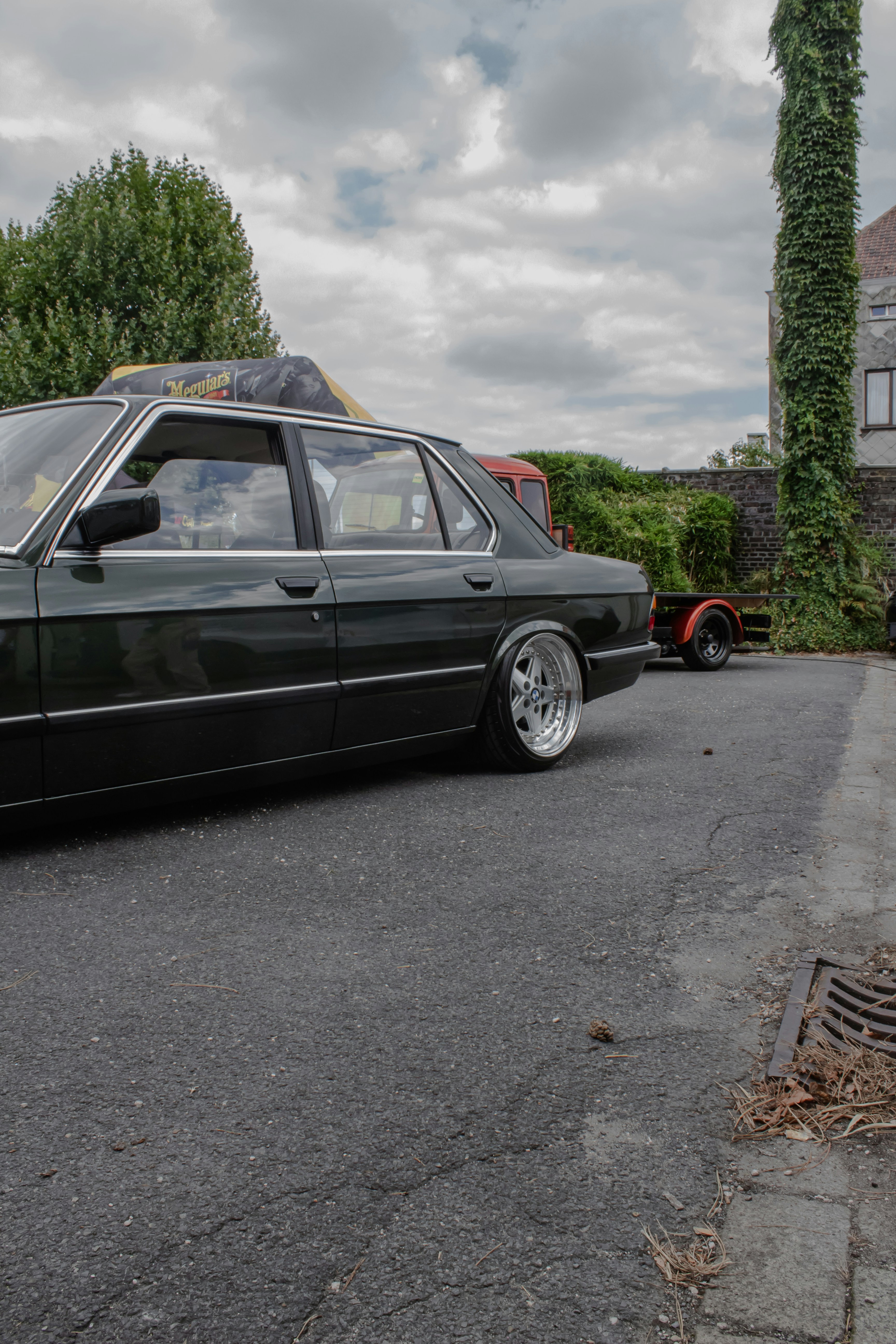 Polished Rear-Wheel Portrait: A Green Vintage Sedan in a Quiet Yard