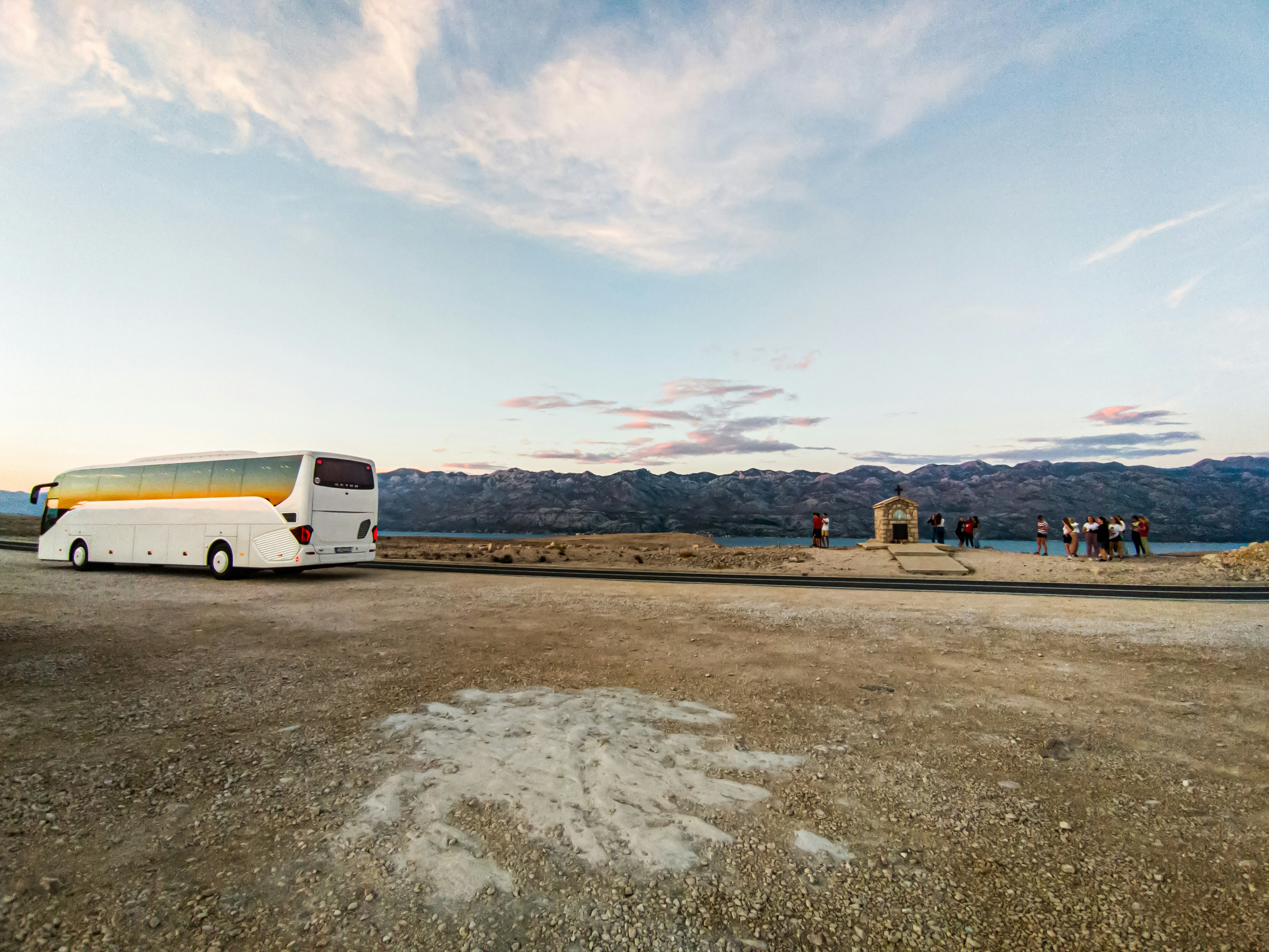 Rim Stopover: A White Tour Bus Pauses at the Plateau's Edge as Explorers Gather