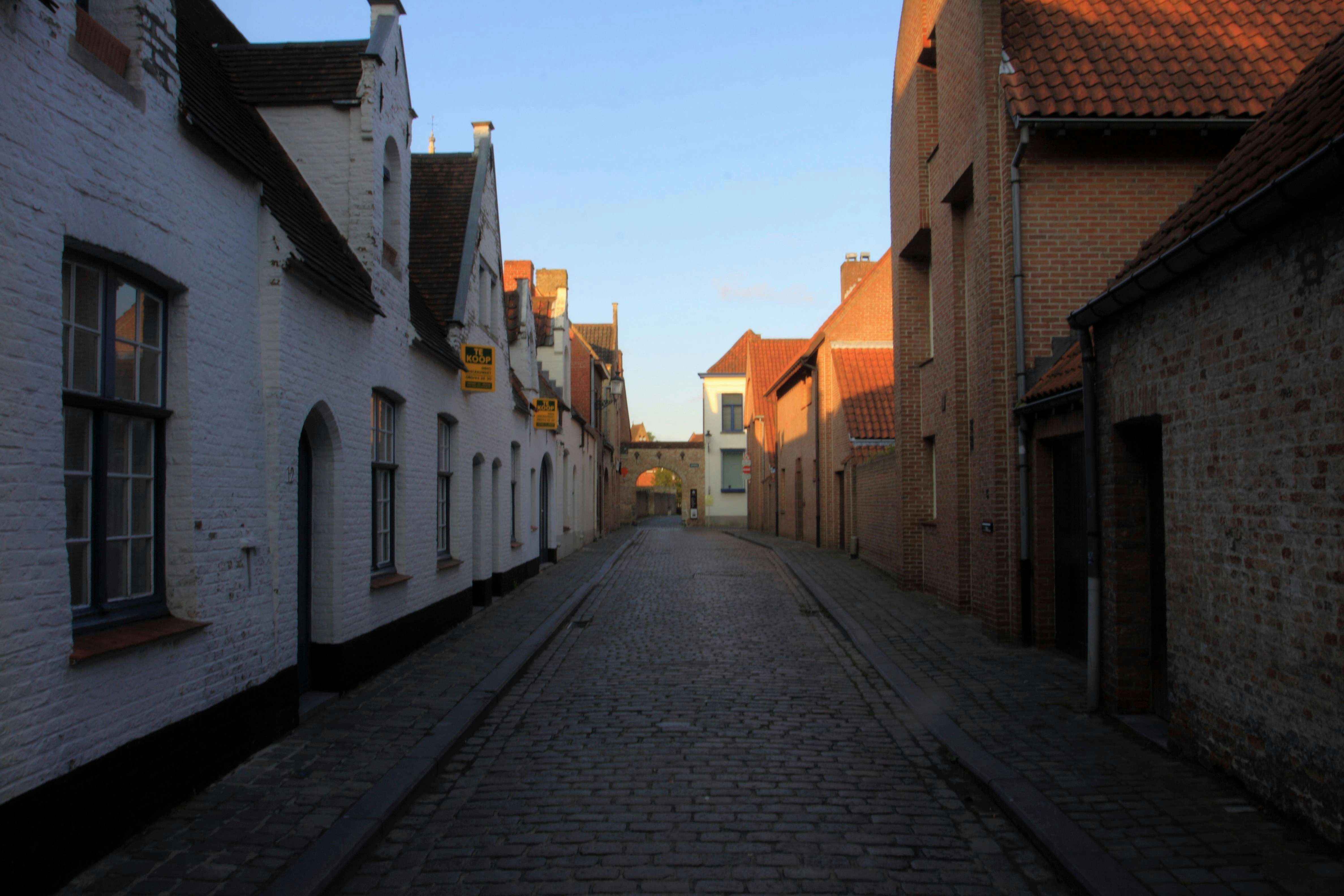 A cobblestone street between buildings photo – Free Sunset Image on ...