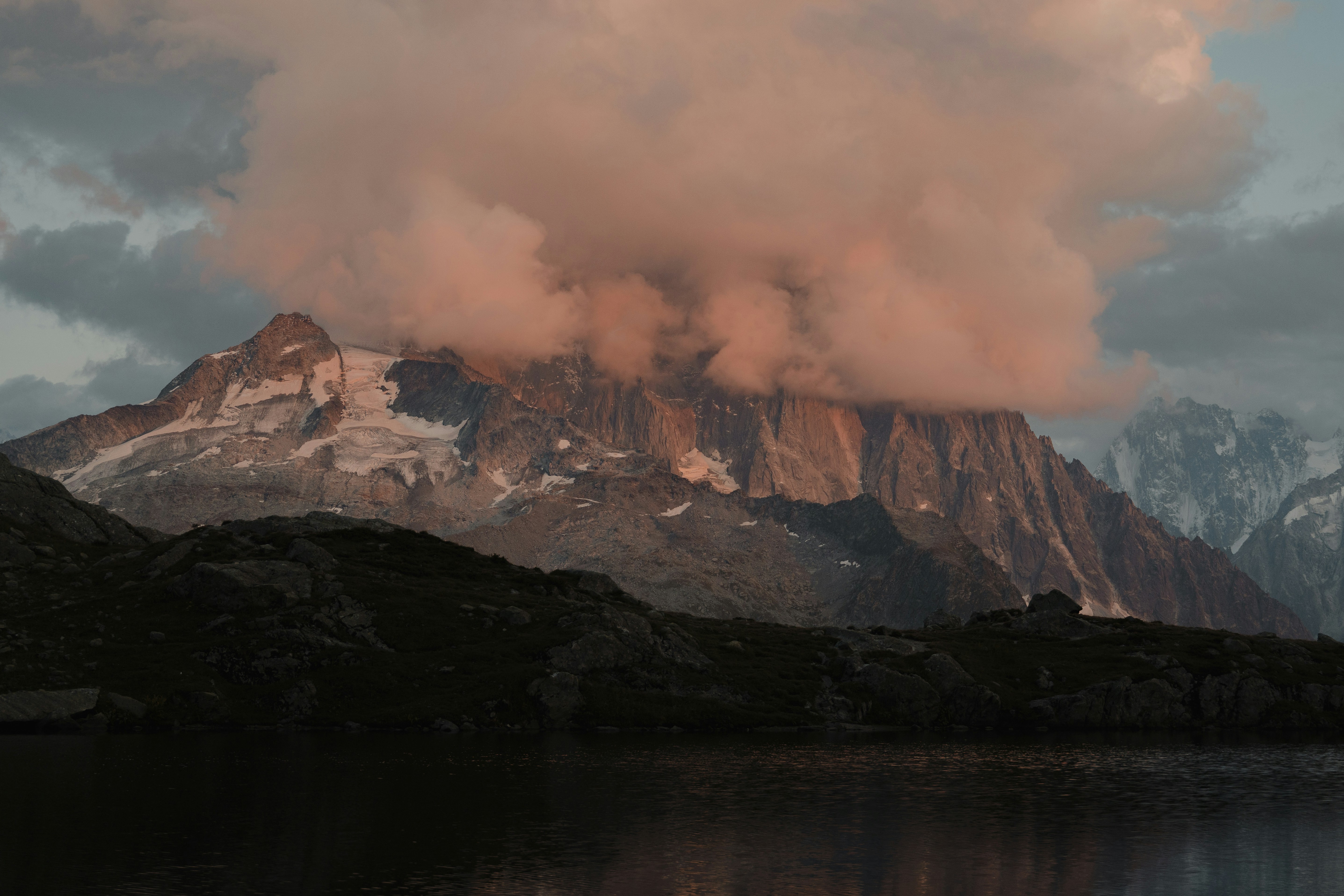 Crimson Summit: Cloud-Claimed Peaks Over a Quiet Tarn