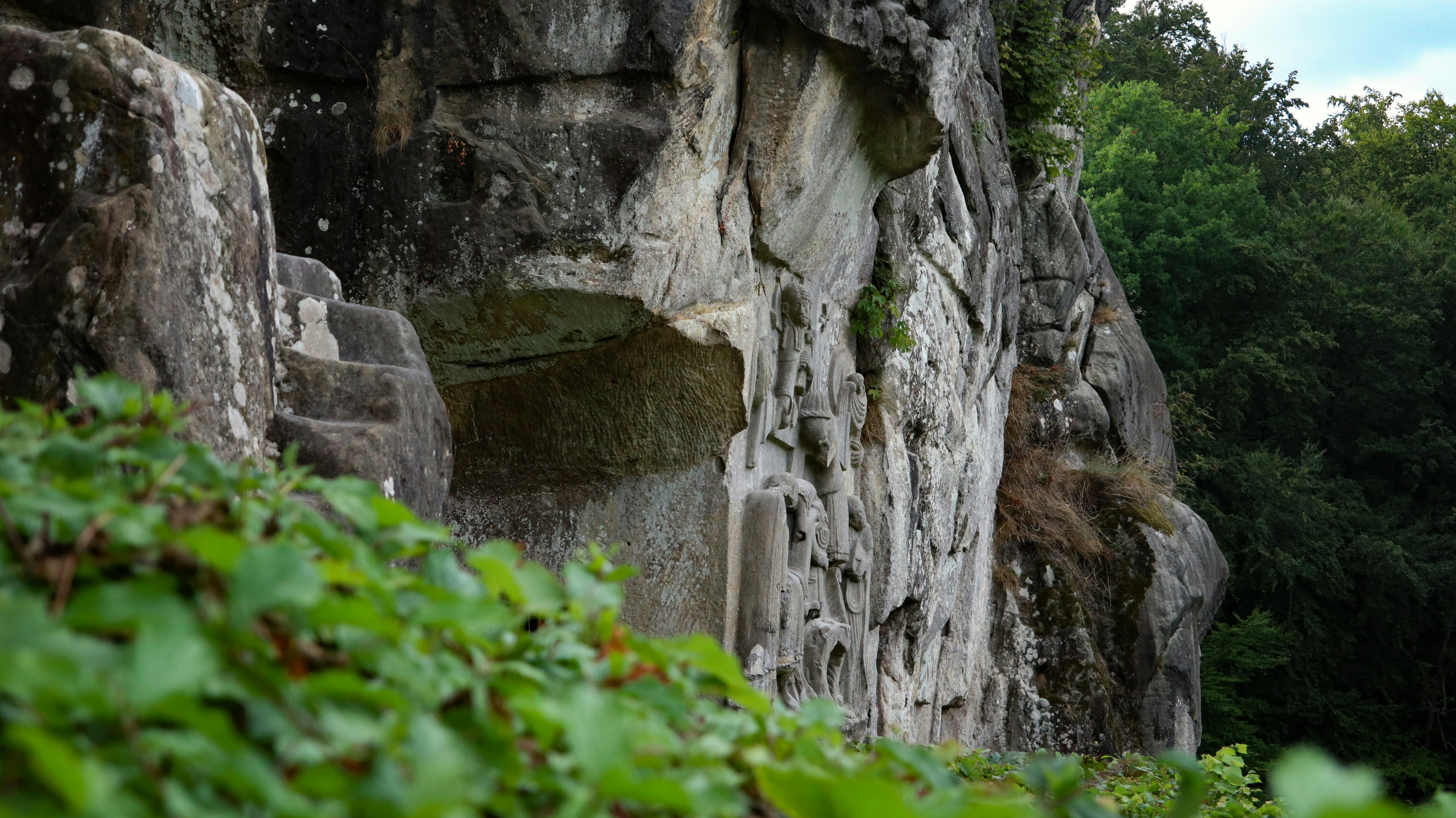 Stone Faces in the Cliff: A Quiet Carved Narrative by the Green Verge