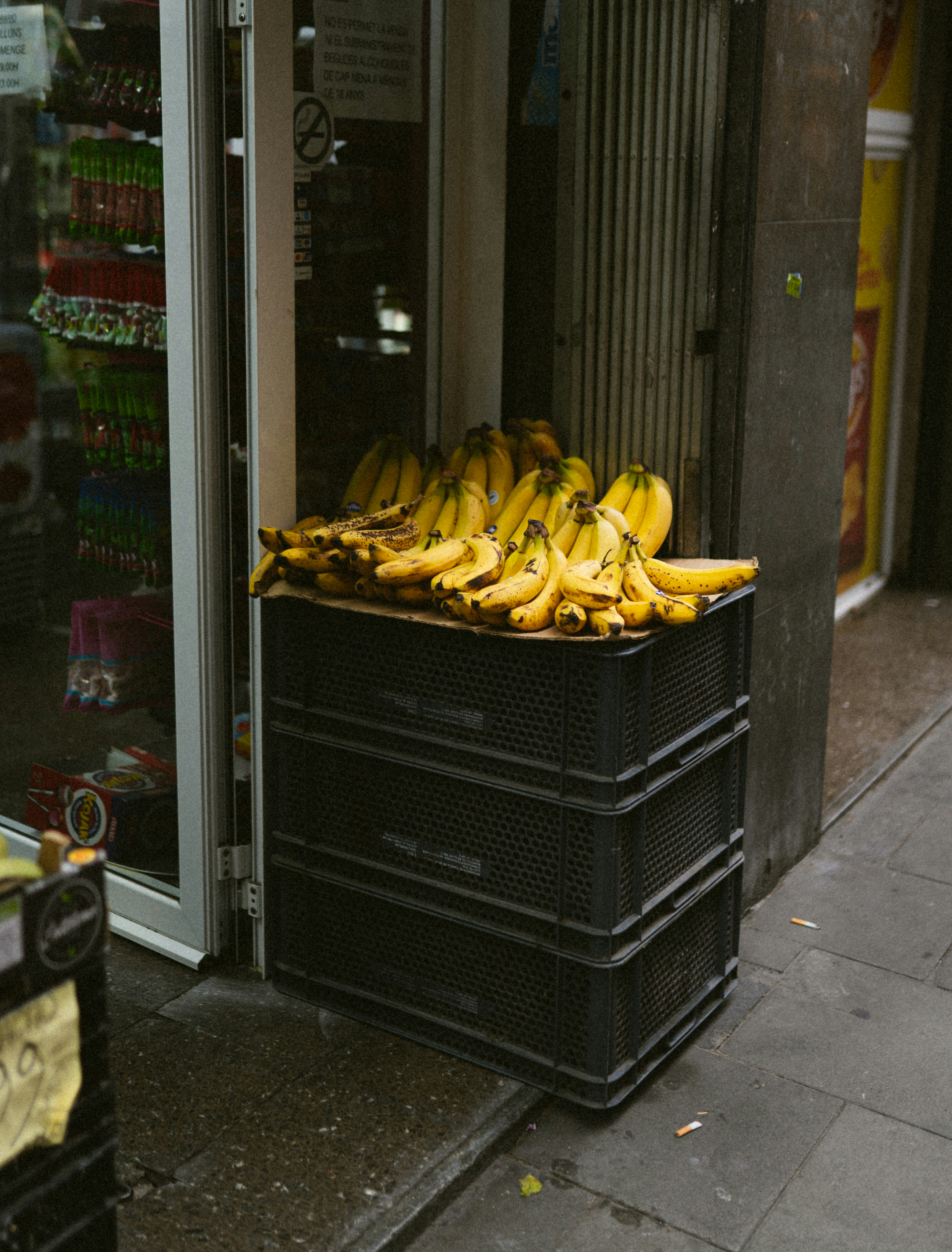 A vibrant display of ripe bananas stacked in crates outside a corner store, showcasing the hustle of urban life.