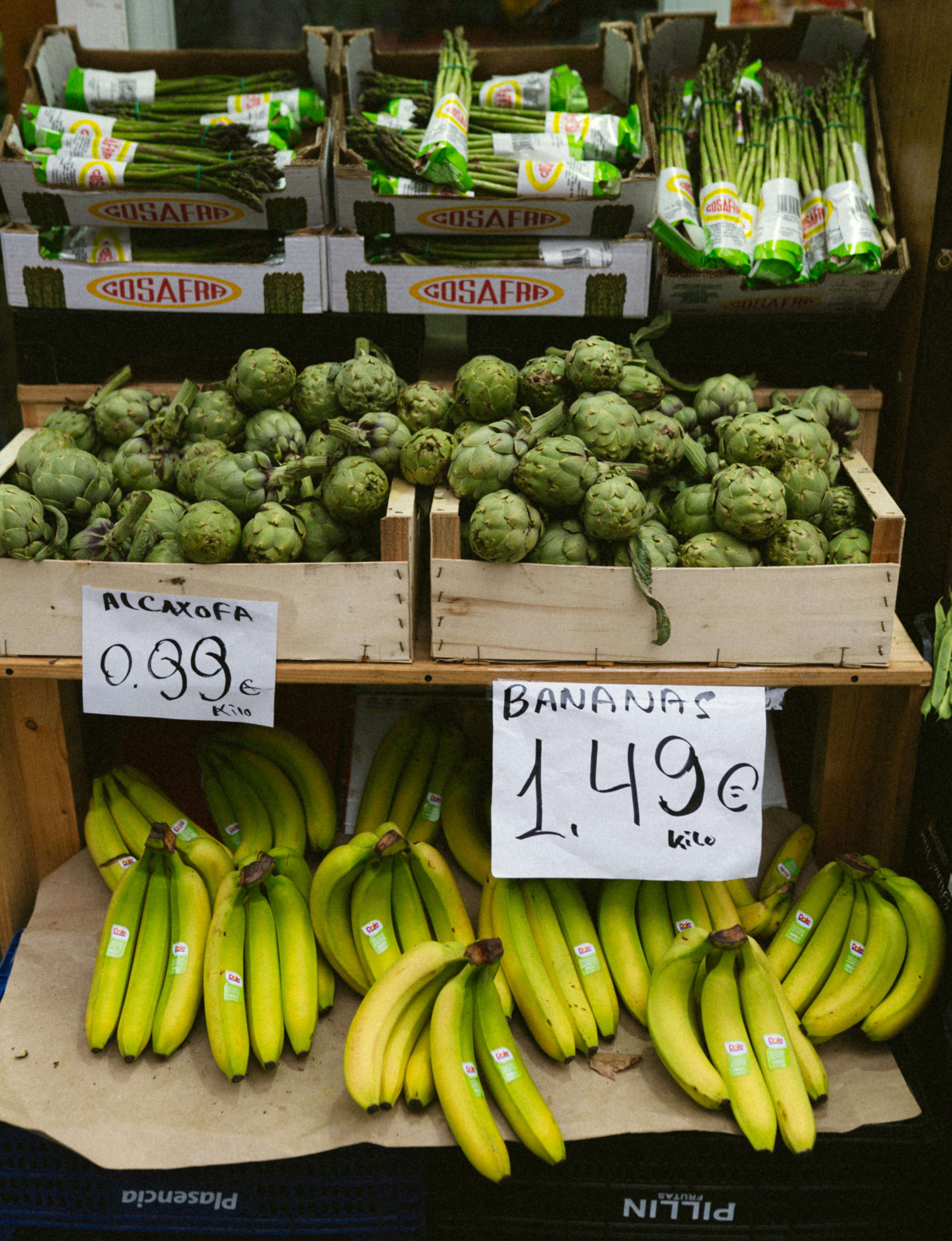 Fresh artichokes and ripe bananas arranged in a market stall, showcasing vibrant colors and price tags. A visual feast for produce lovers.