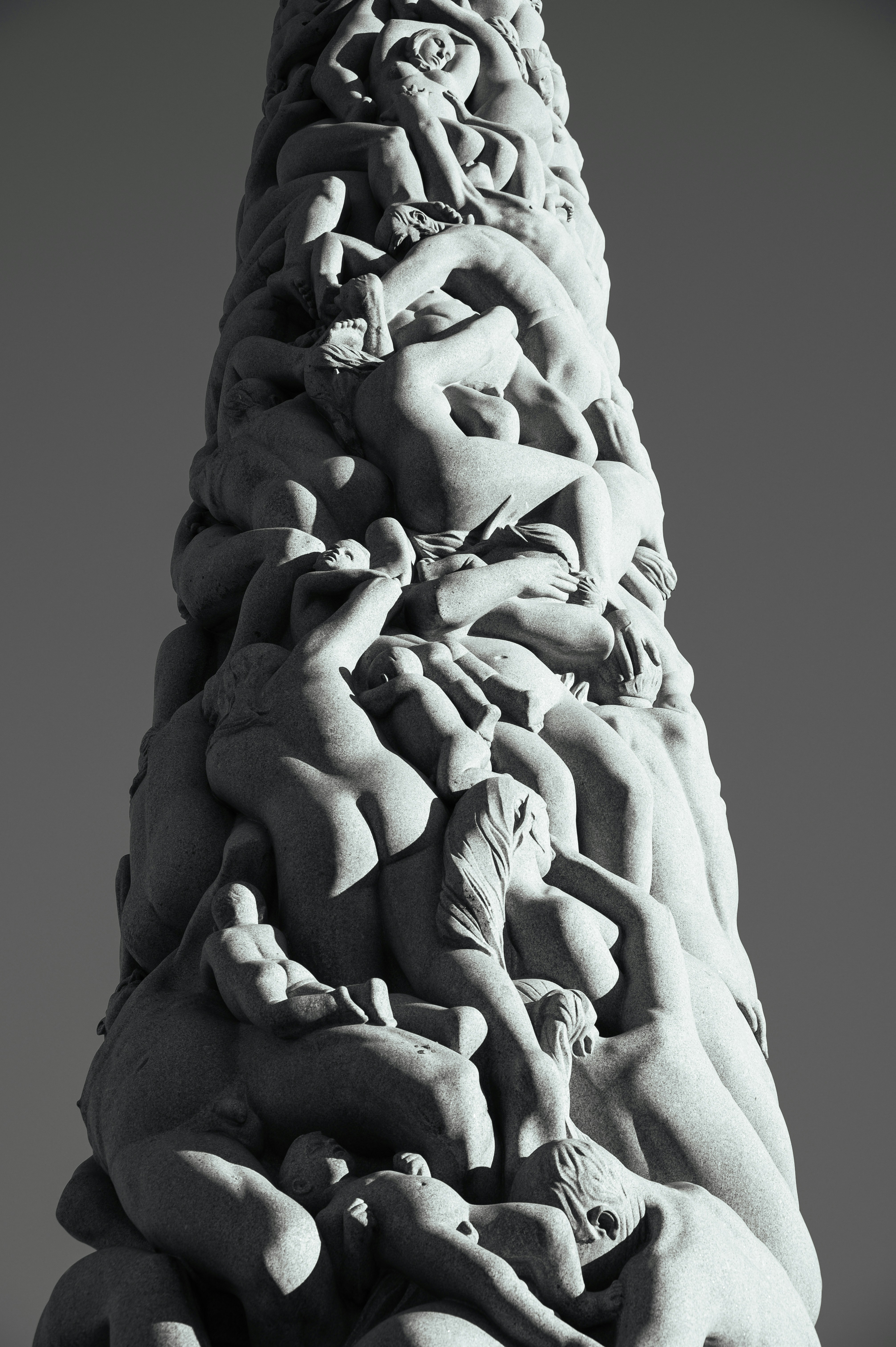 Intricately carved stone column featuring entwined human figures in dynamic poses, showcasing the complexities of human emotion and connection.