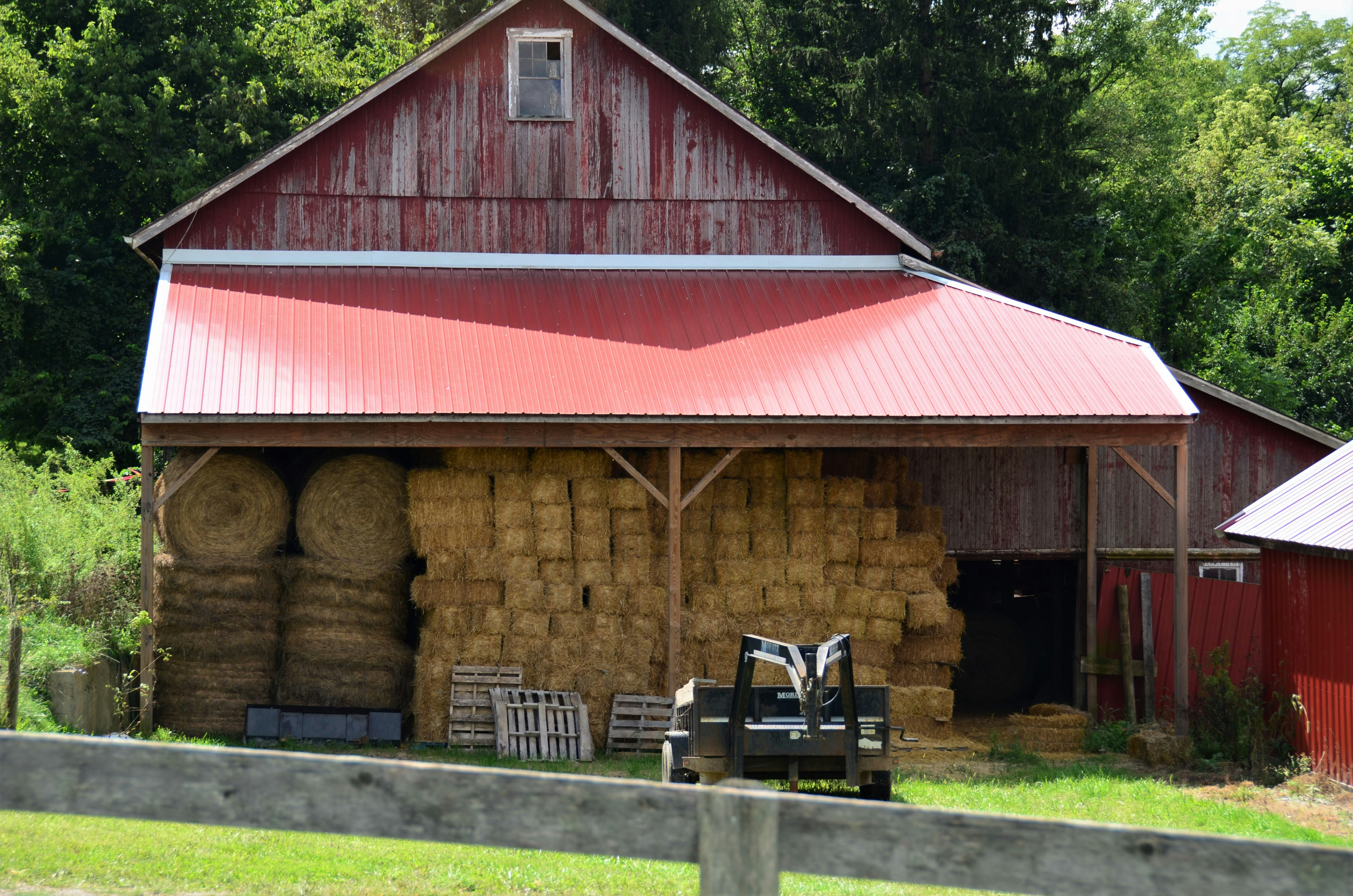 A barn with a large stack of logs in front of it photo – Free Building ...