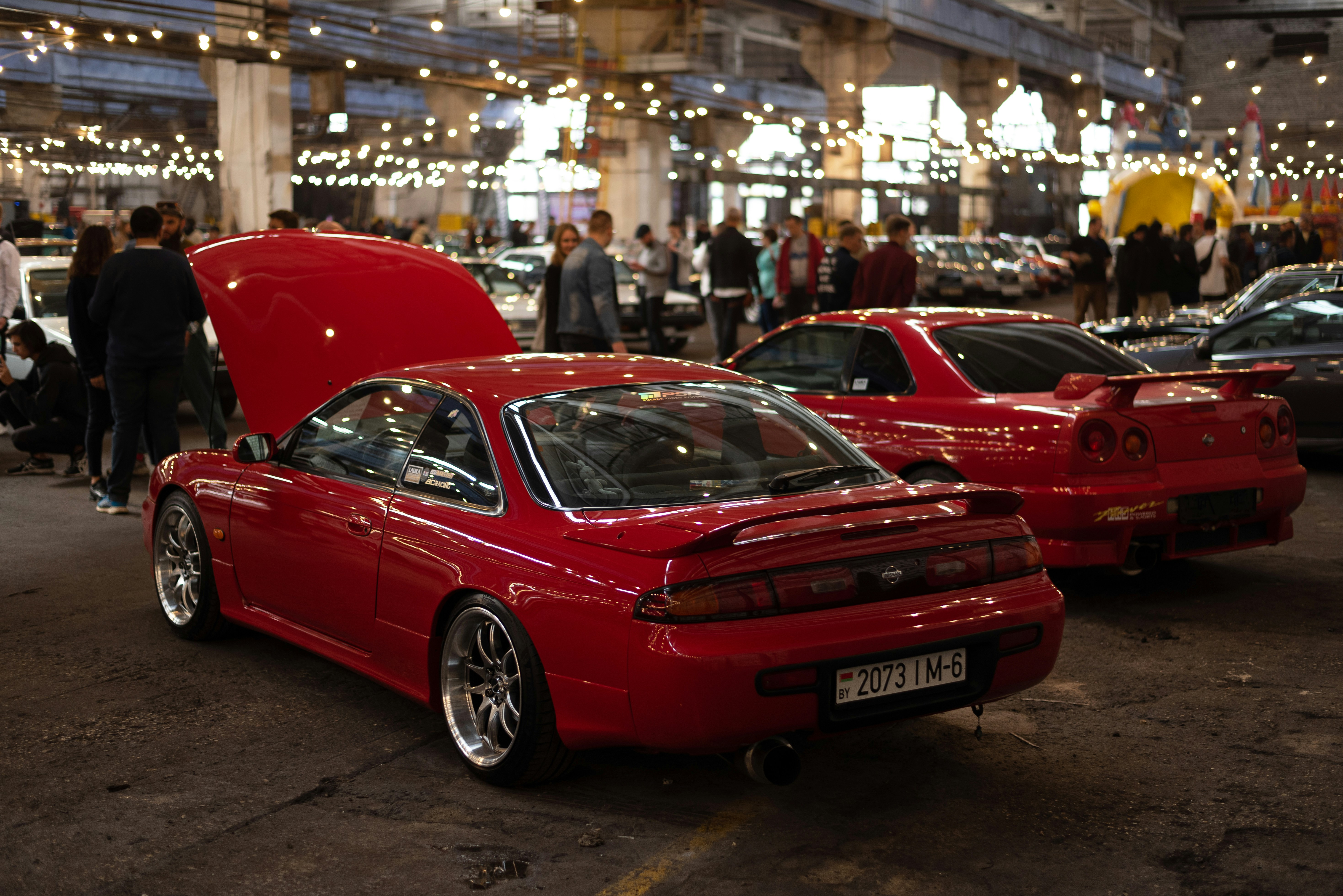 A group of cars parked in a building with people walking around photo ...