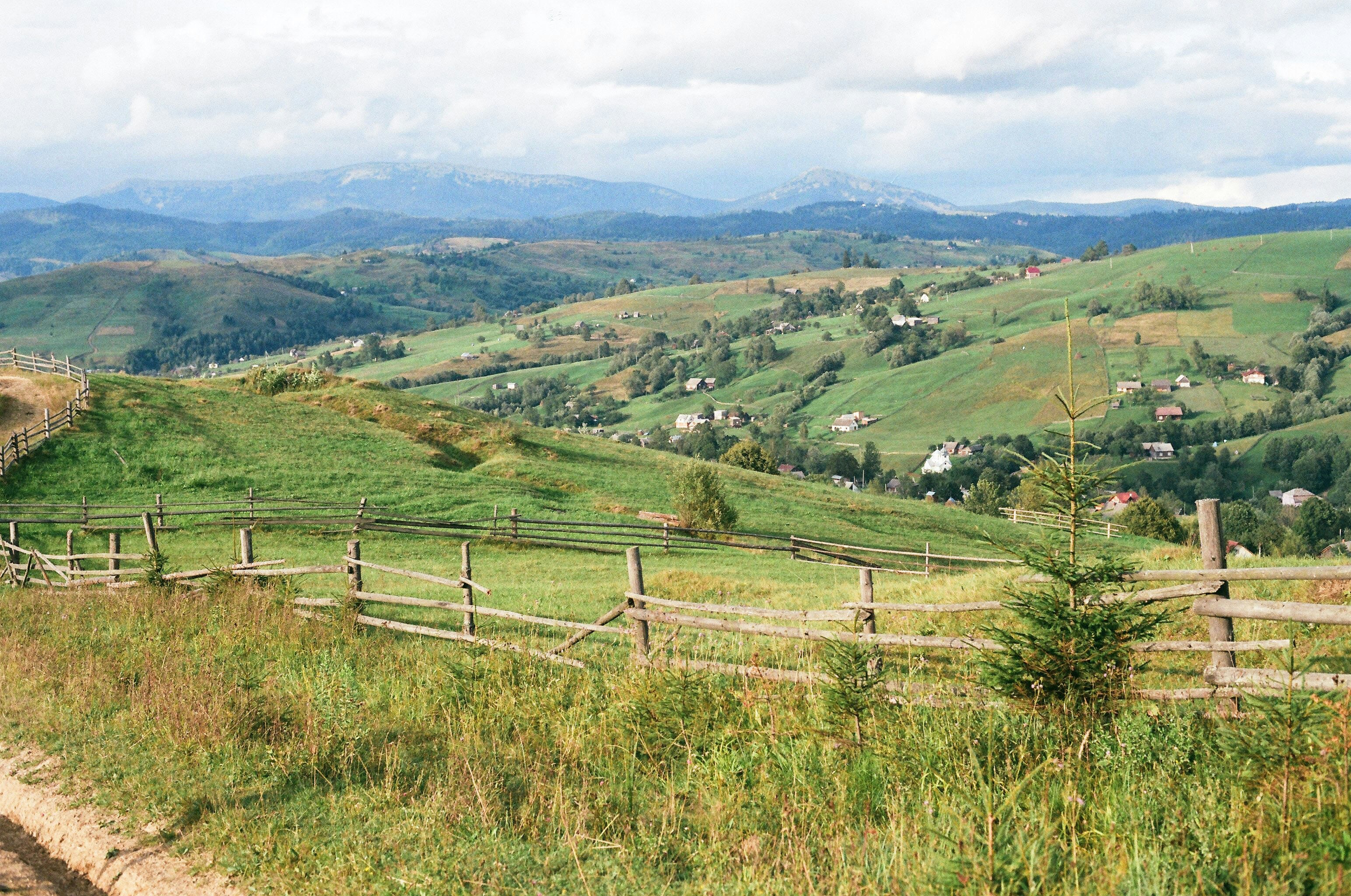 A fenced in field with a wooden fence and a town in the distance photo ...