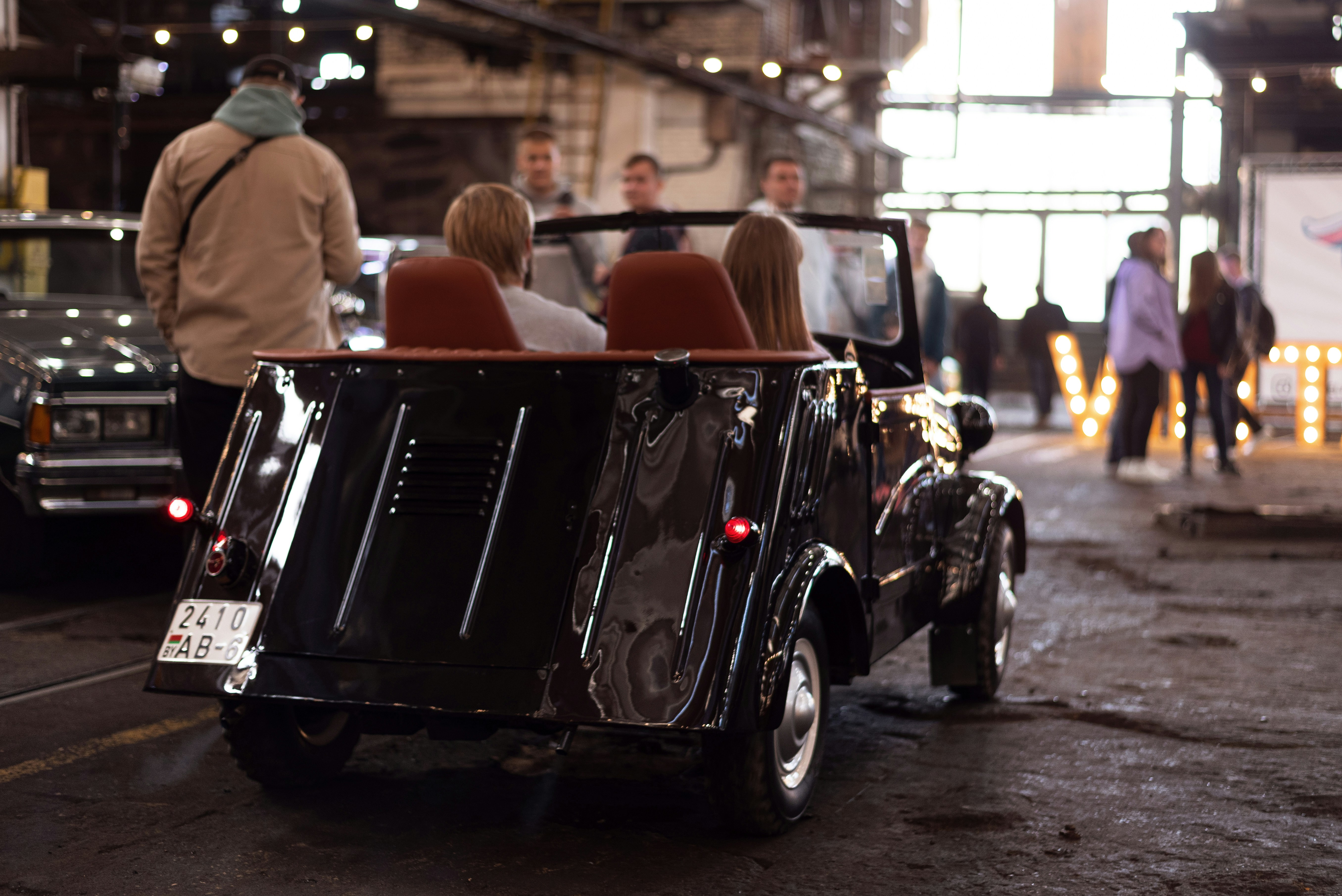 Chrome and Conversation: A Vintage Roadster Beneath Industrial Glow