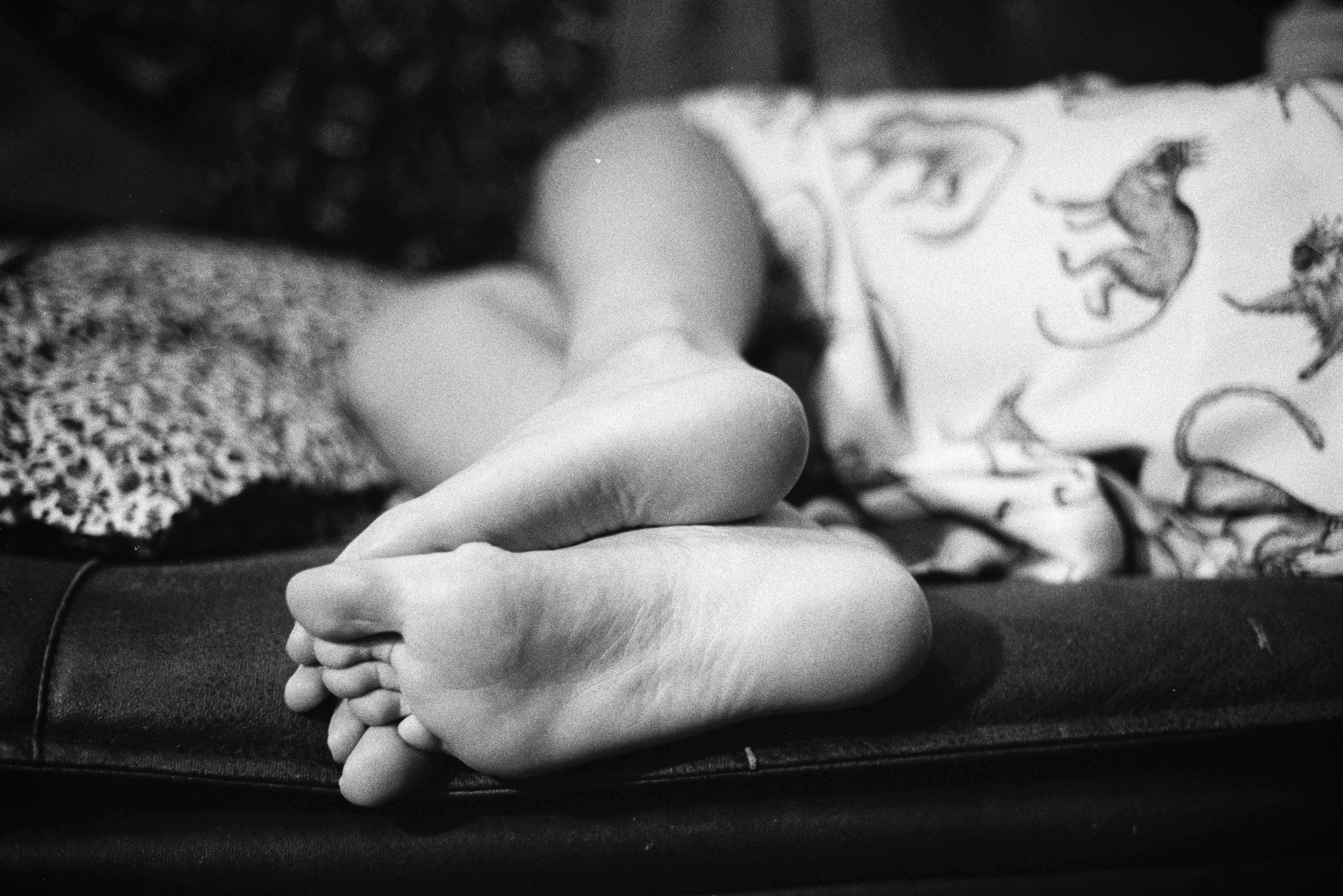 Child's bare feet resting on a couch, surrounded by patterned cushions, evoking a sense of comfort and tranquility.