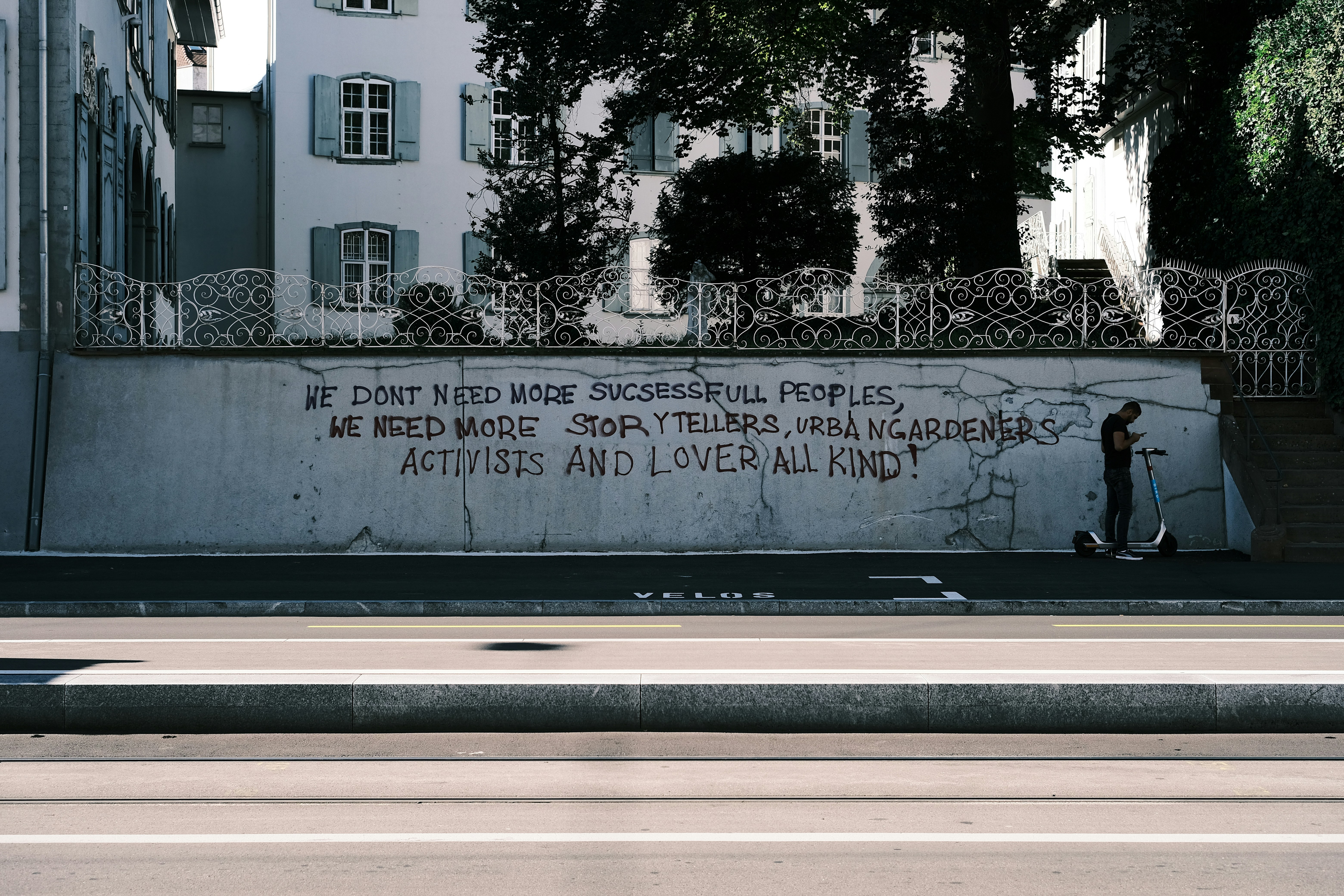 A wall mural featuring a powerful message advocating for storytellers, urban gardeners, activists, and lovers, emphasizing the need for community over success.