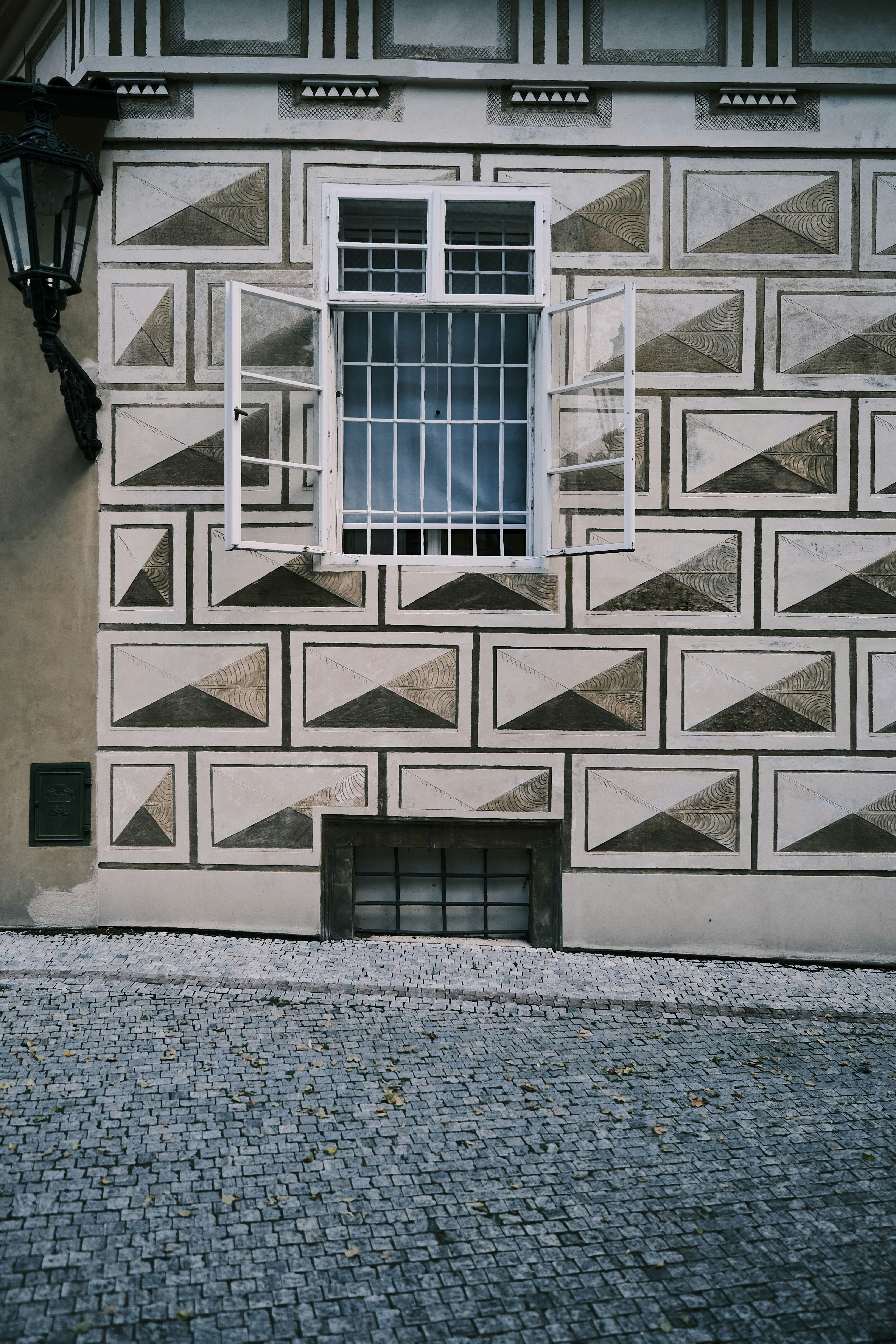 Architectural wall adorned with intricate geometric patterns and an open window, inviting a glimpse into the past.
