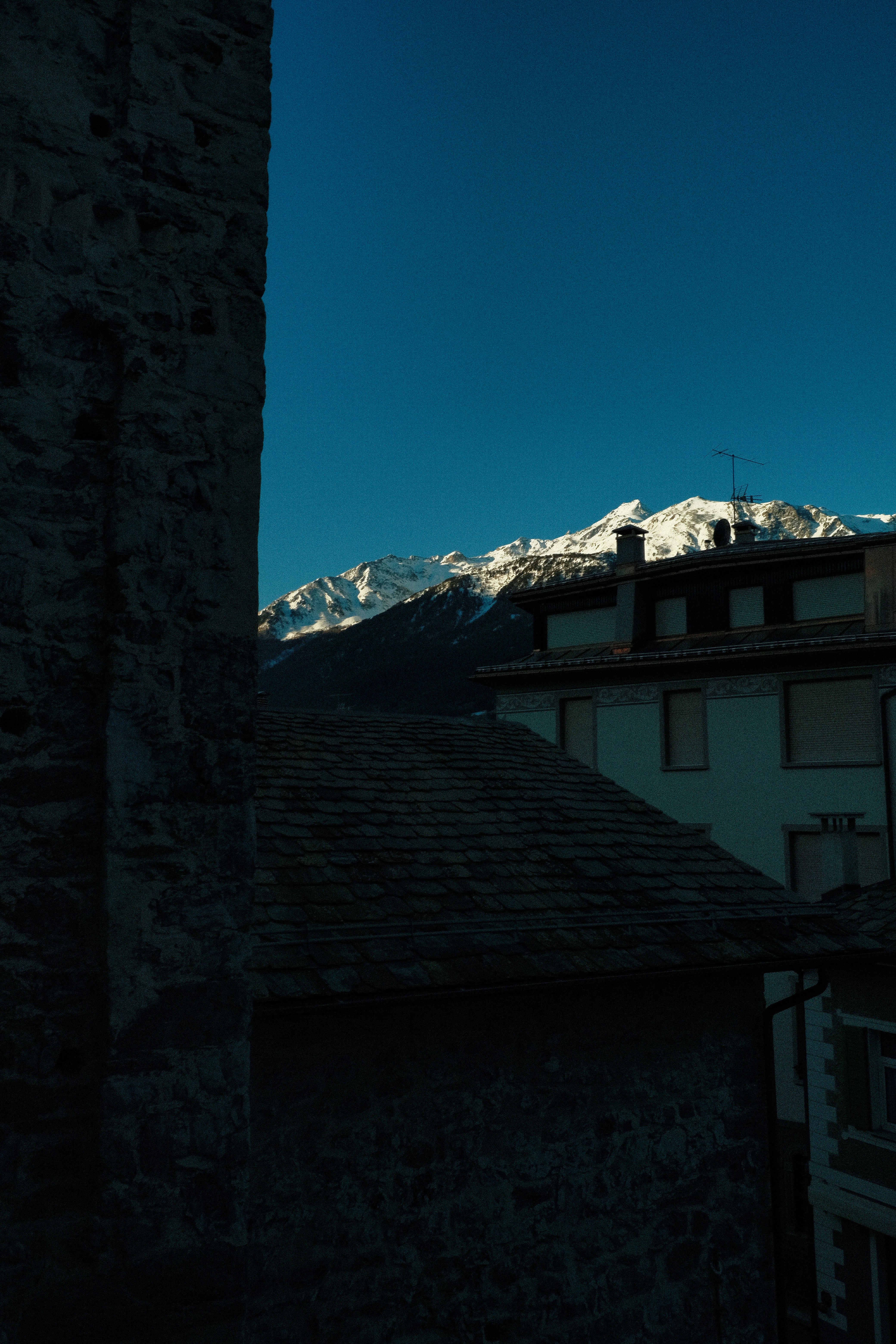 Snow-capped peaks glimmer over a shadowed European street