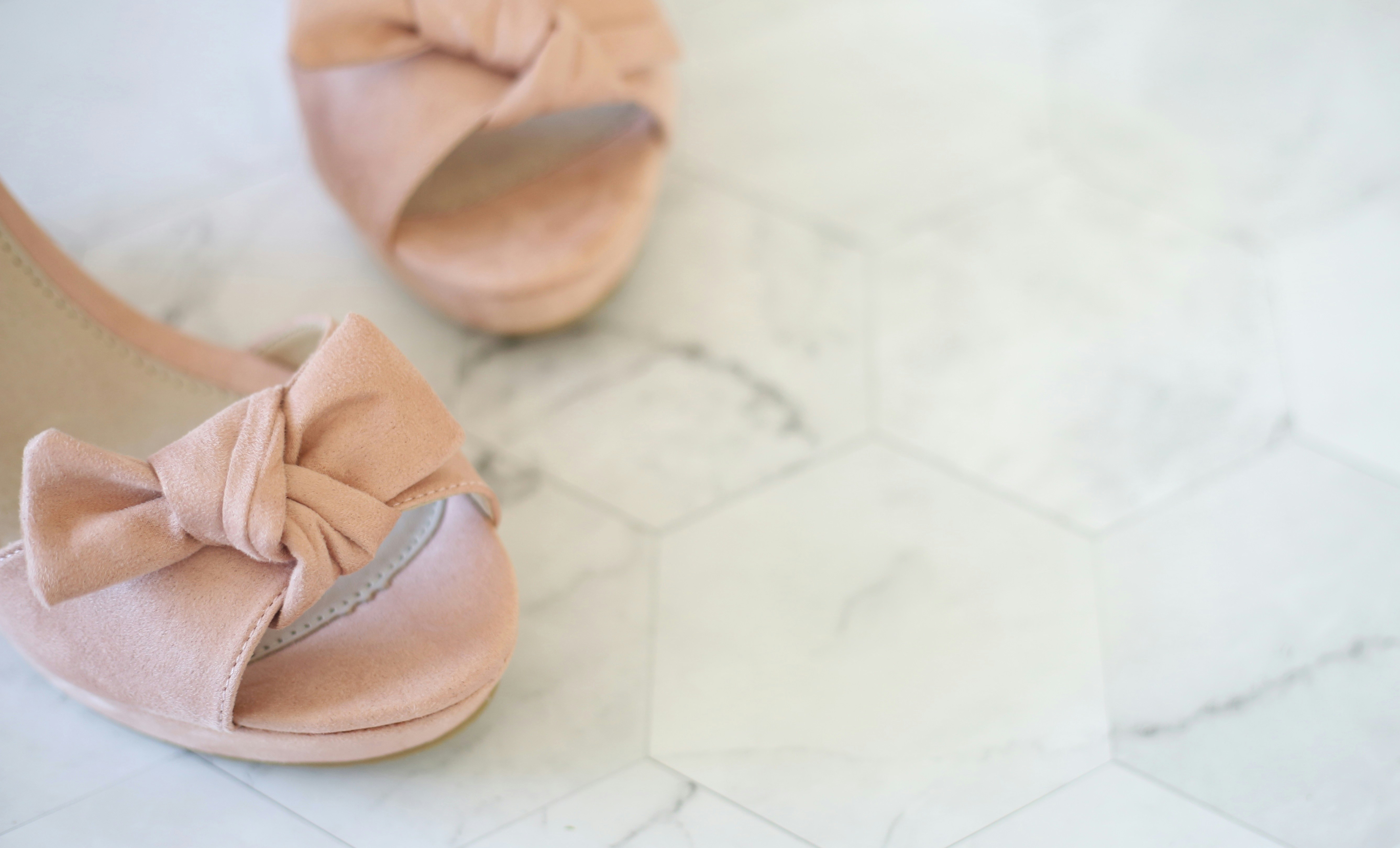 Pastel Pedals: Soft Pink Baby Shoes Resting on Marble Tiles